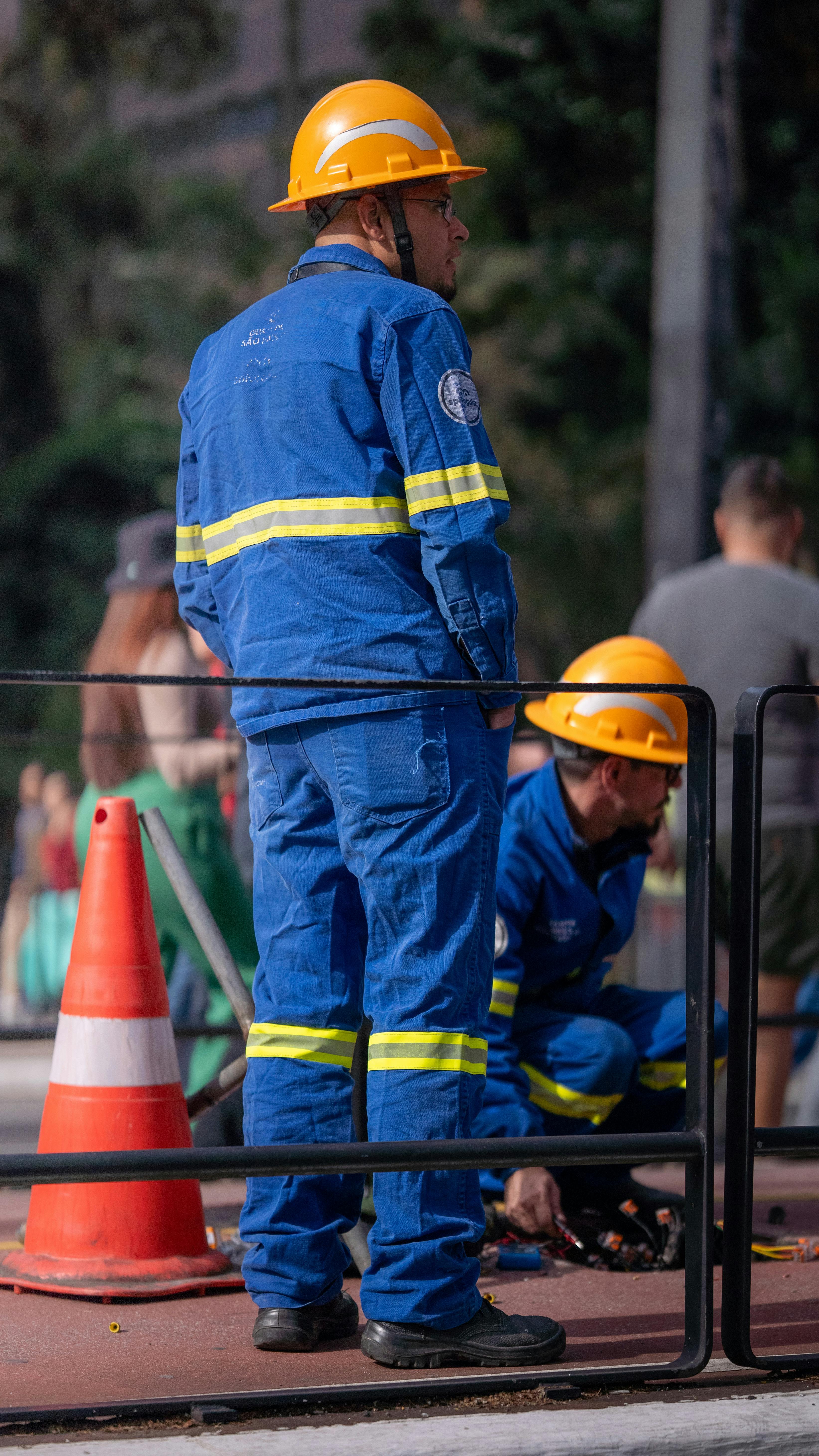 Two men in blue and yellow work clothes standing next to each other ...