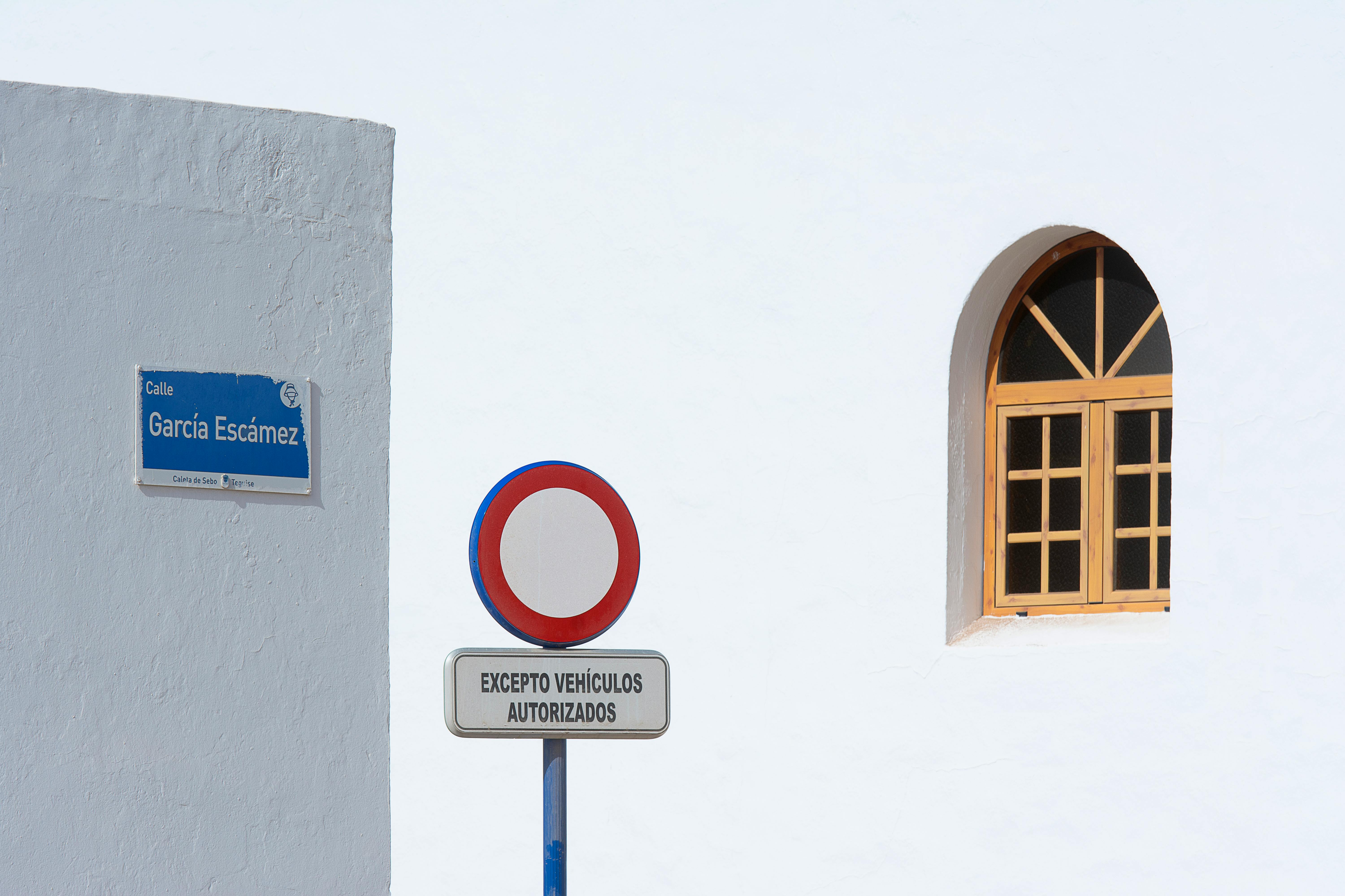 A white building with a sign and a street sign · Free Stock Photo