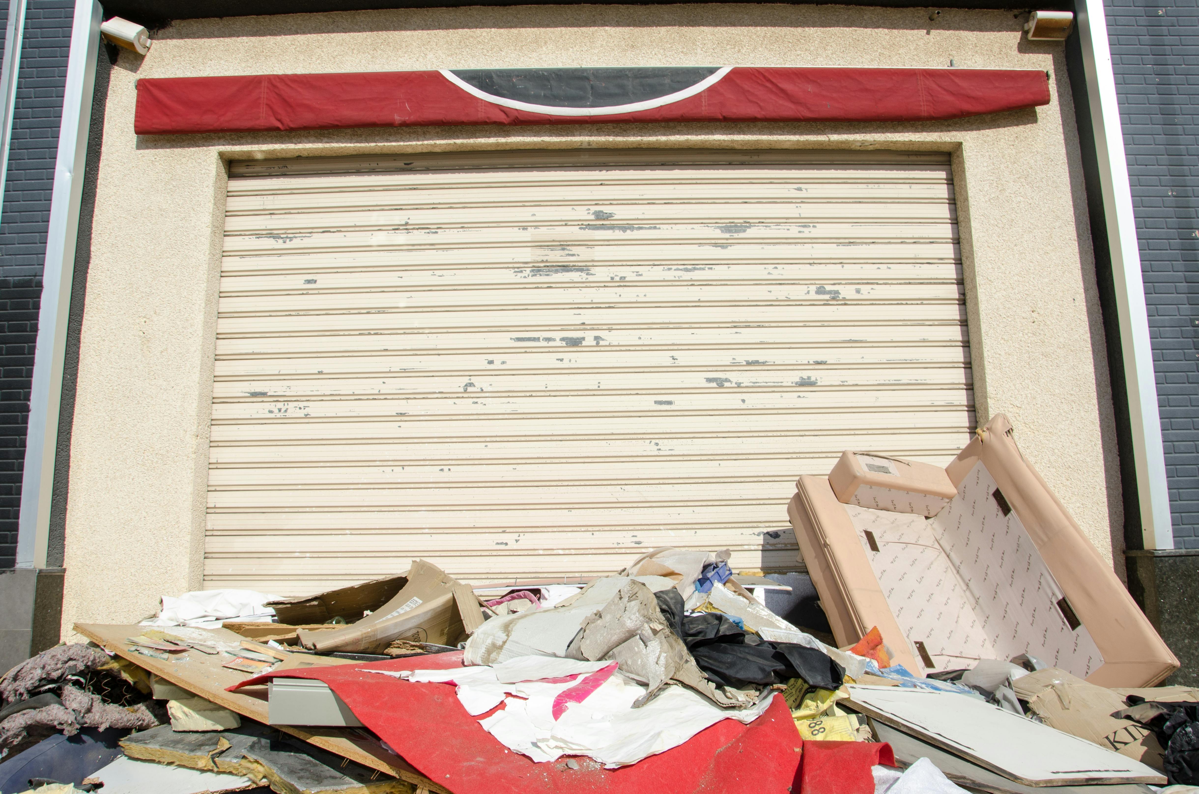 Urban Shopfront with Piled Waste and Broken Shutter · Free Stock Photo