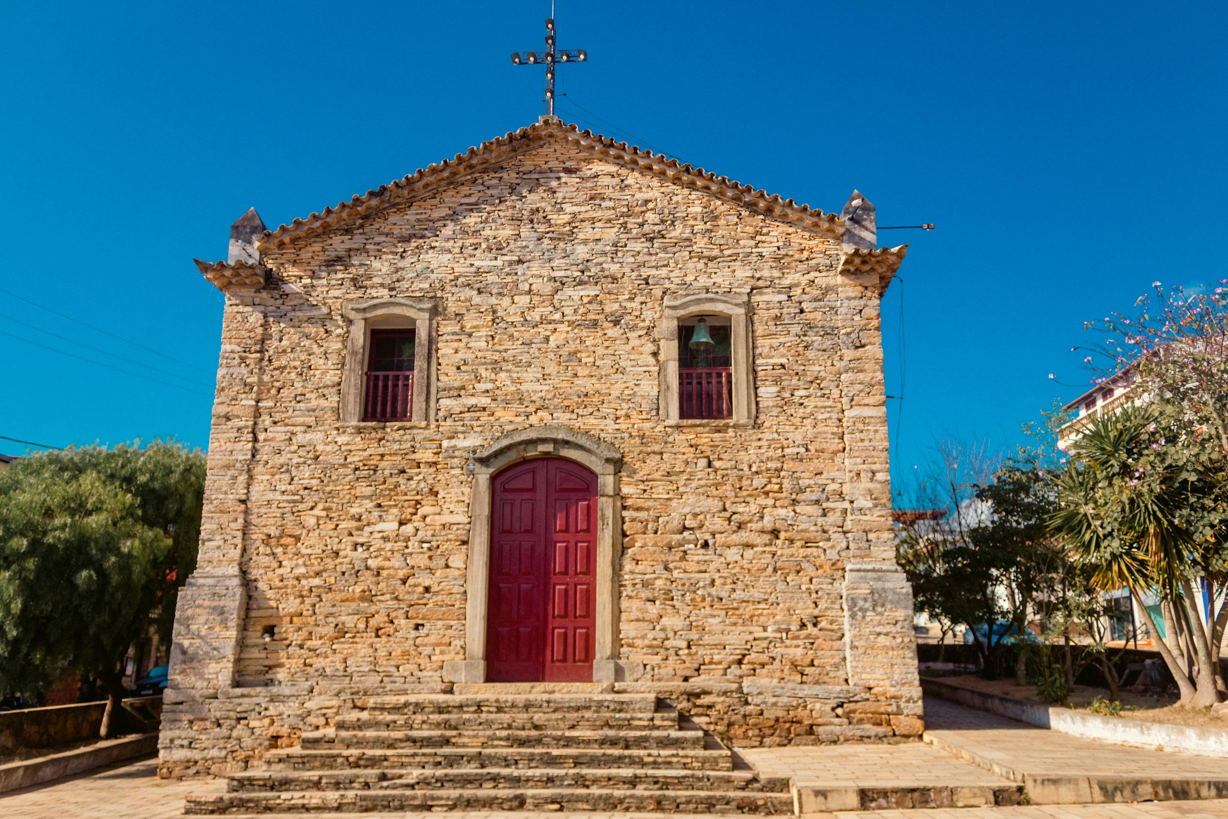 A small stone church with red doors and steps · Free Stock Photo