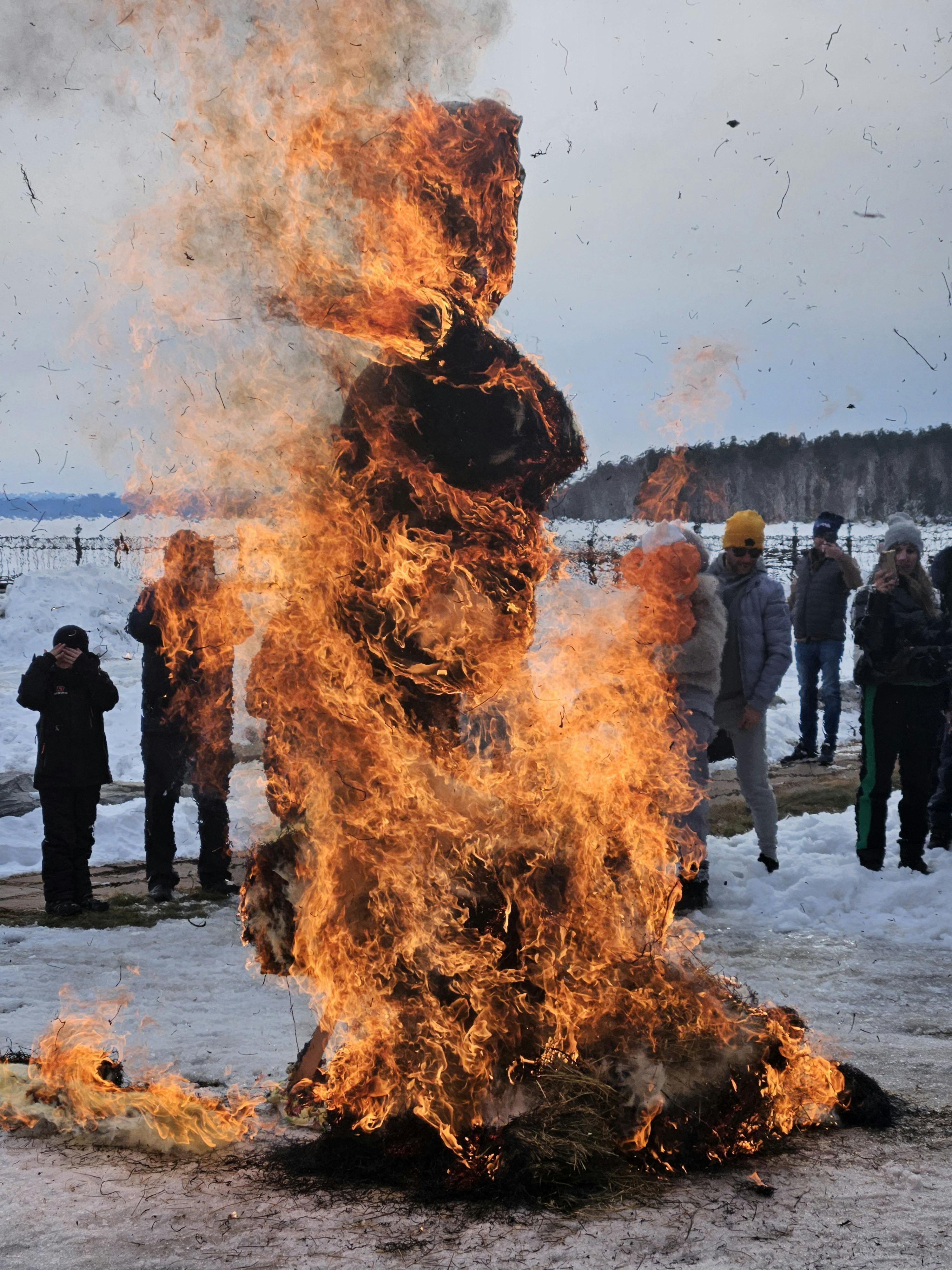 A man is standing in front of a fire with people around him · Free ...