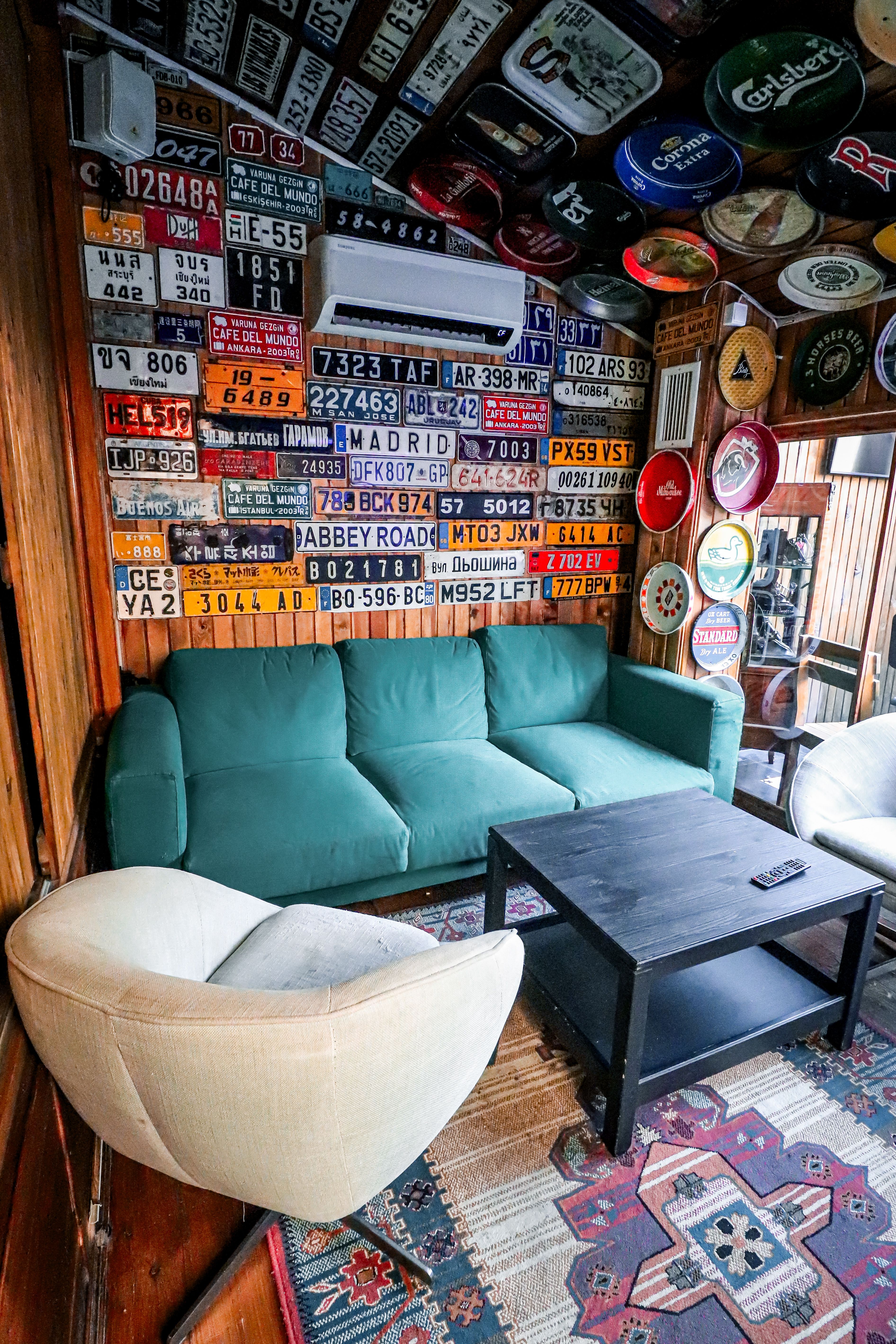 The living room has a couch, coffee table and a wall of license plates ...