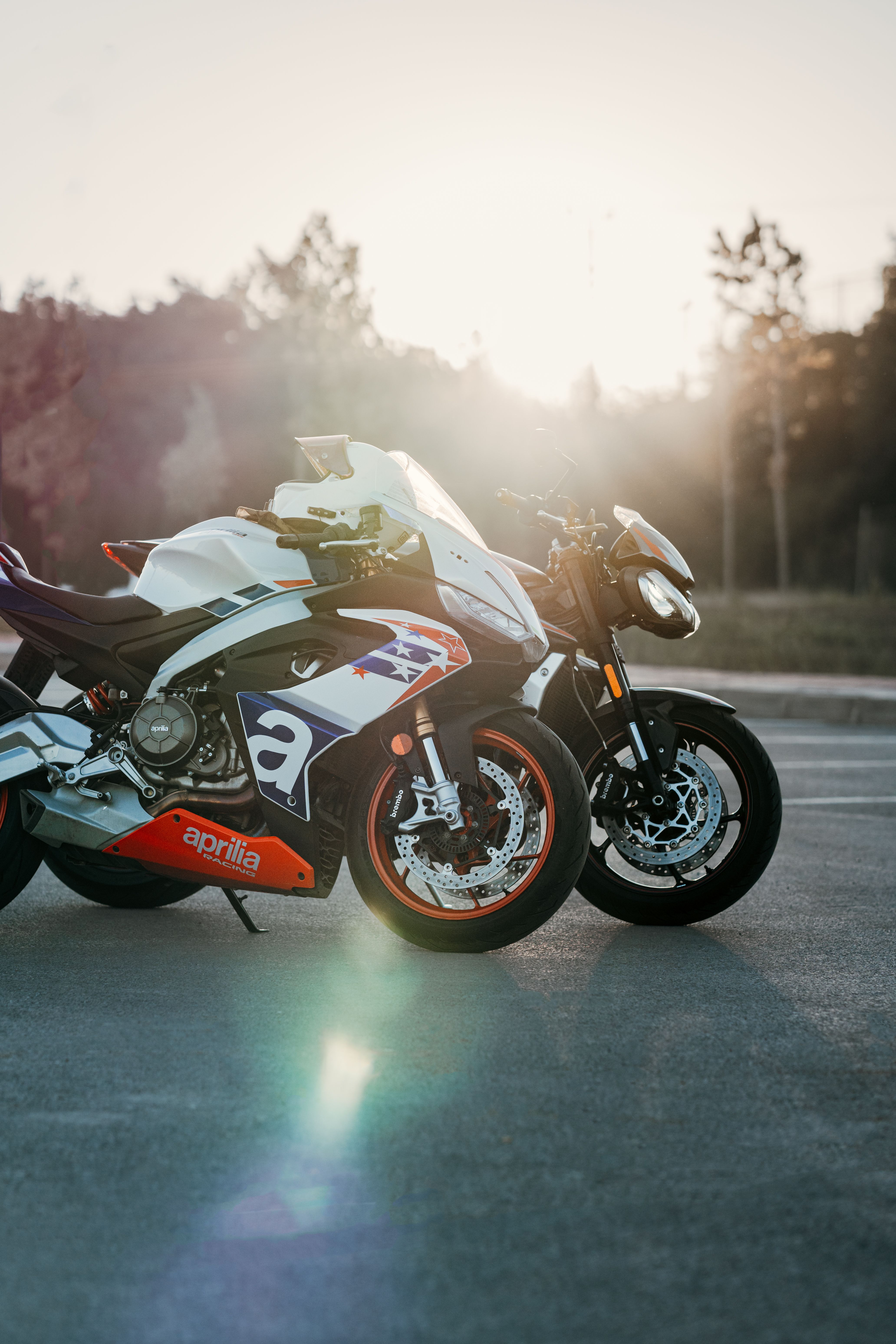 Two motorcycles parked in the sun on a paved road · Free Stock Photo