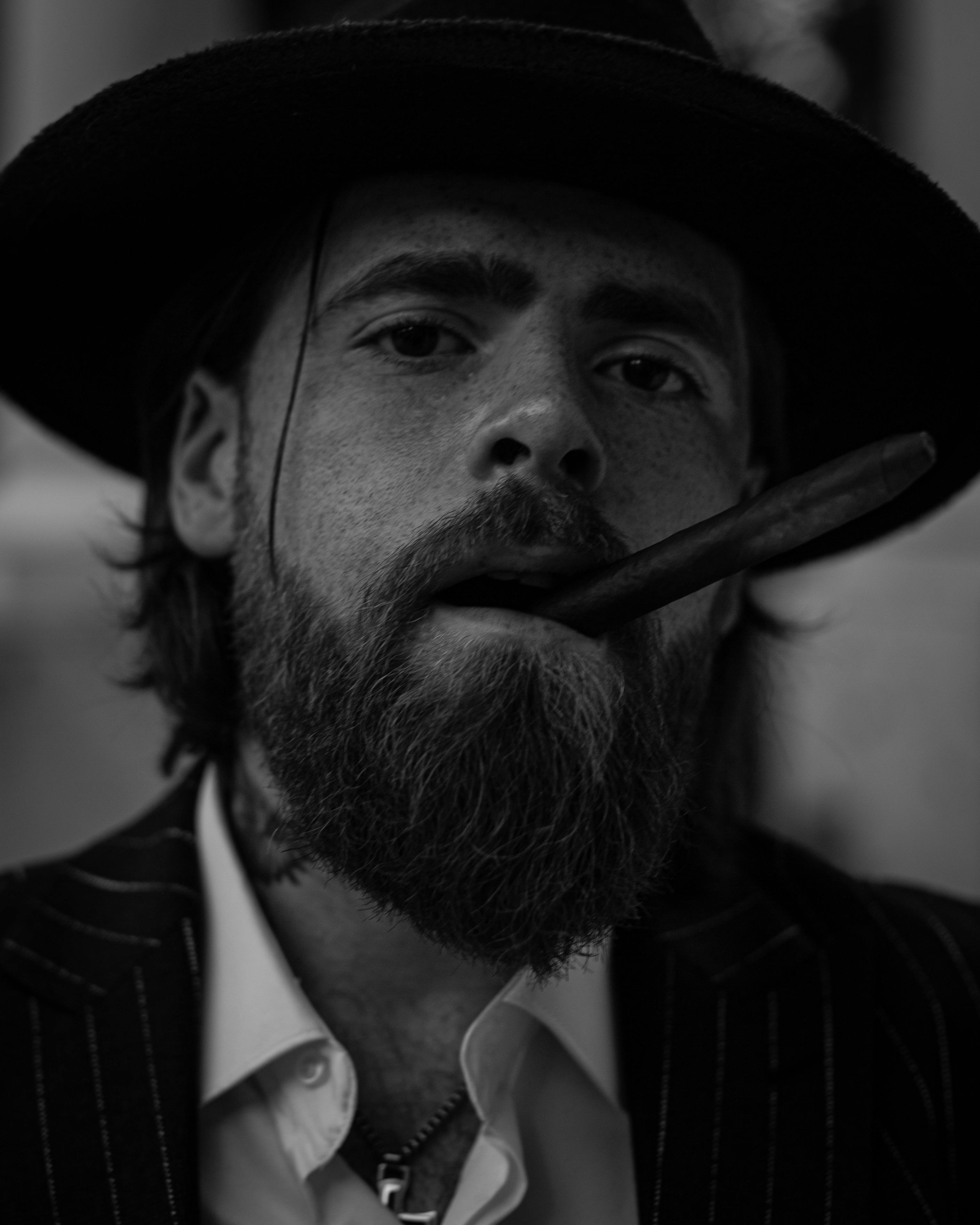 A man with a beard and hat smoking a cigar · Free Stock Photo