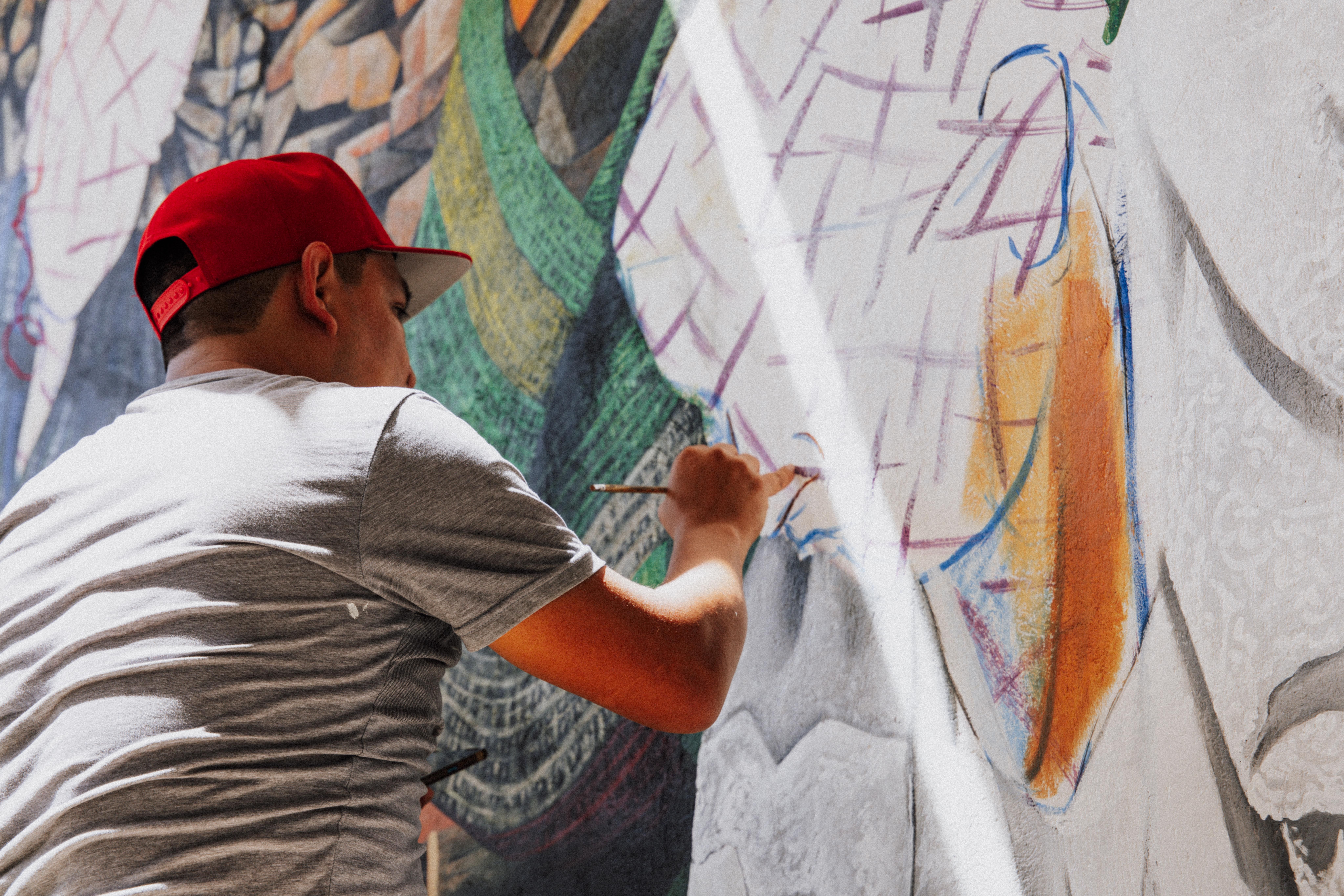 A man in a red hat is painting a mural · Free Stock Photo