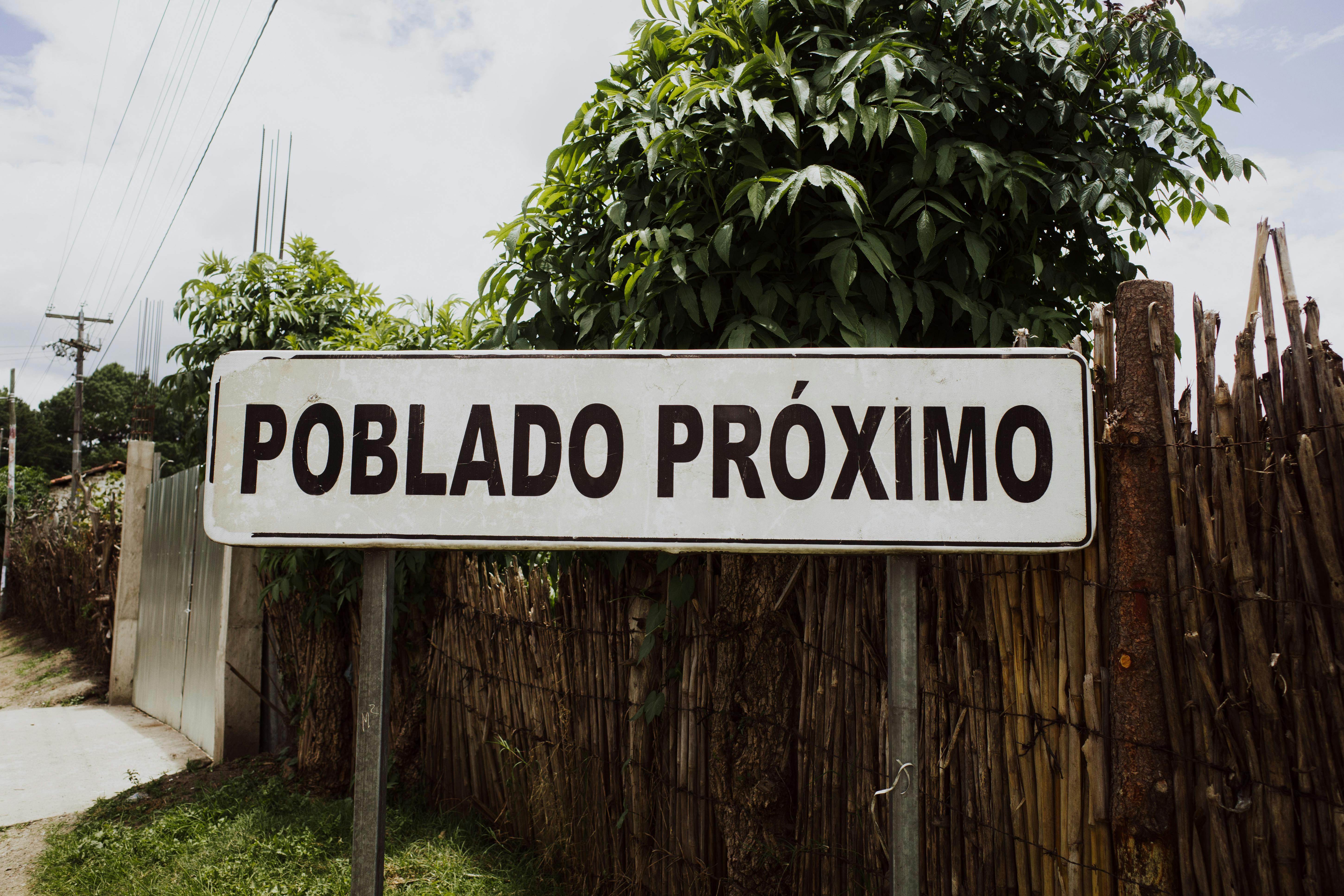 A sign that says poblado proximo in front of a fence · Free Stock Photo