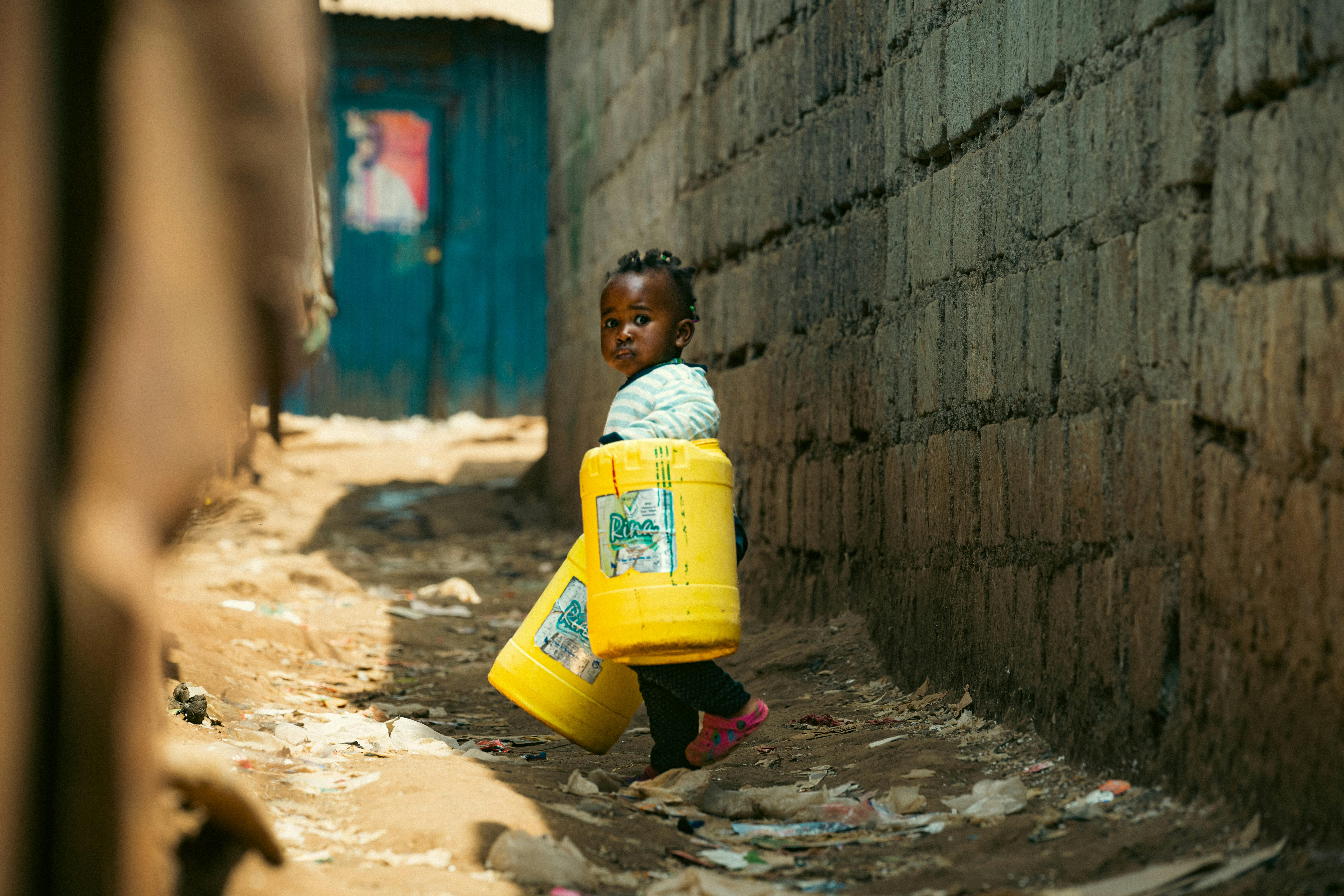 A young girl carrying two buckets of water · Free Stock Photo