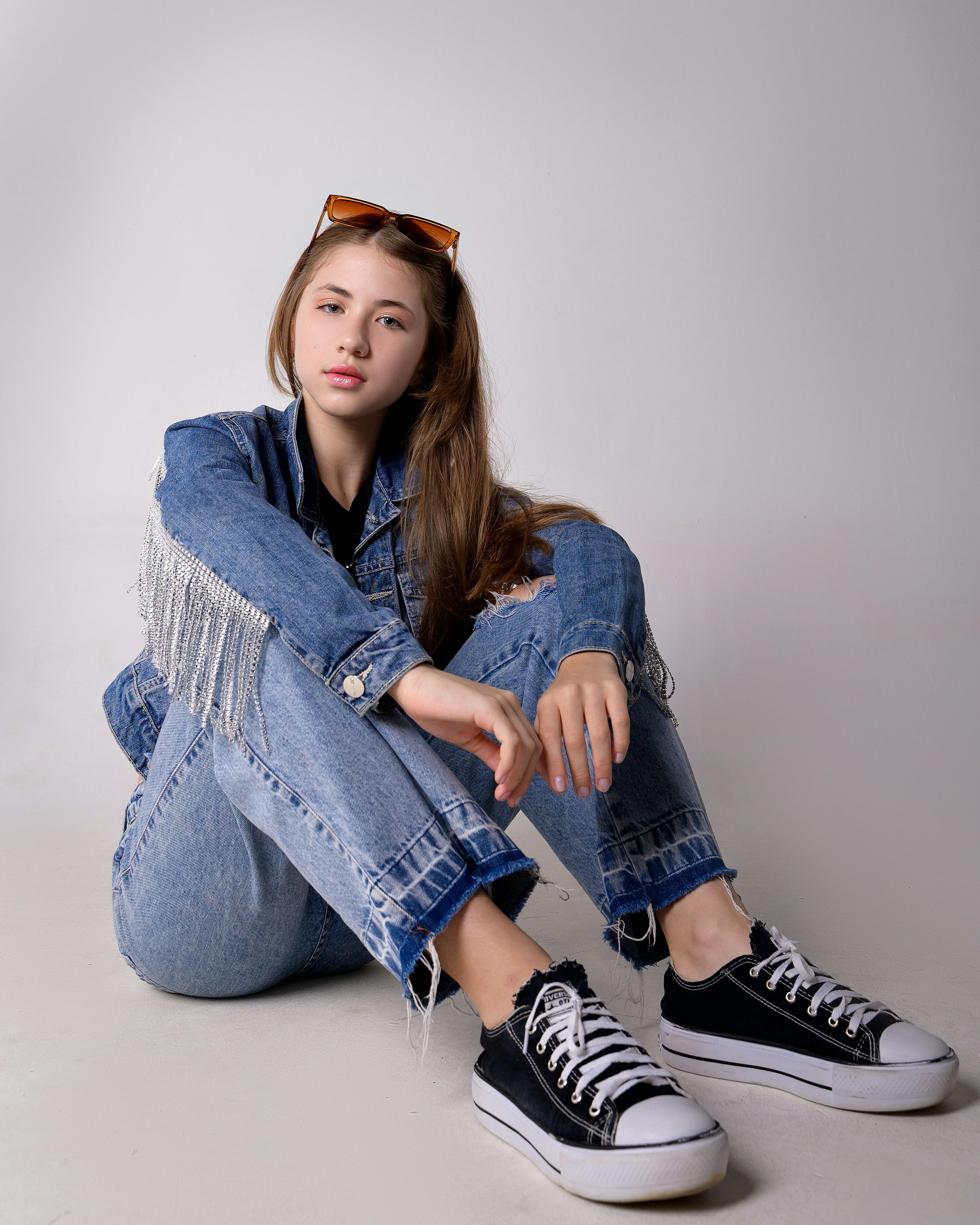 A girl in jeans and sneakers sitting on the floor · Free Stock Photo