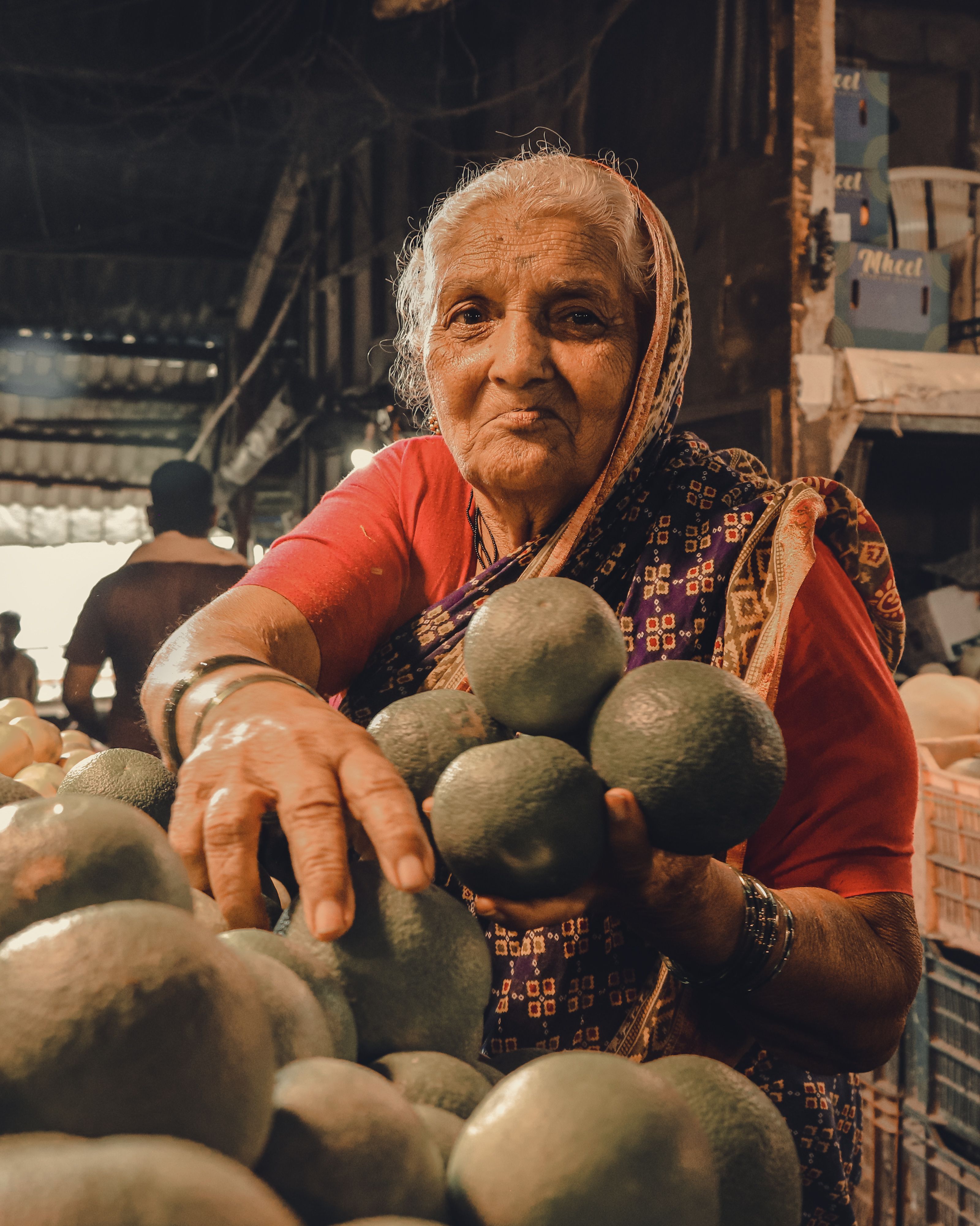An old woman holding a bunch of mangoes · Free Stock Photo