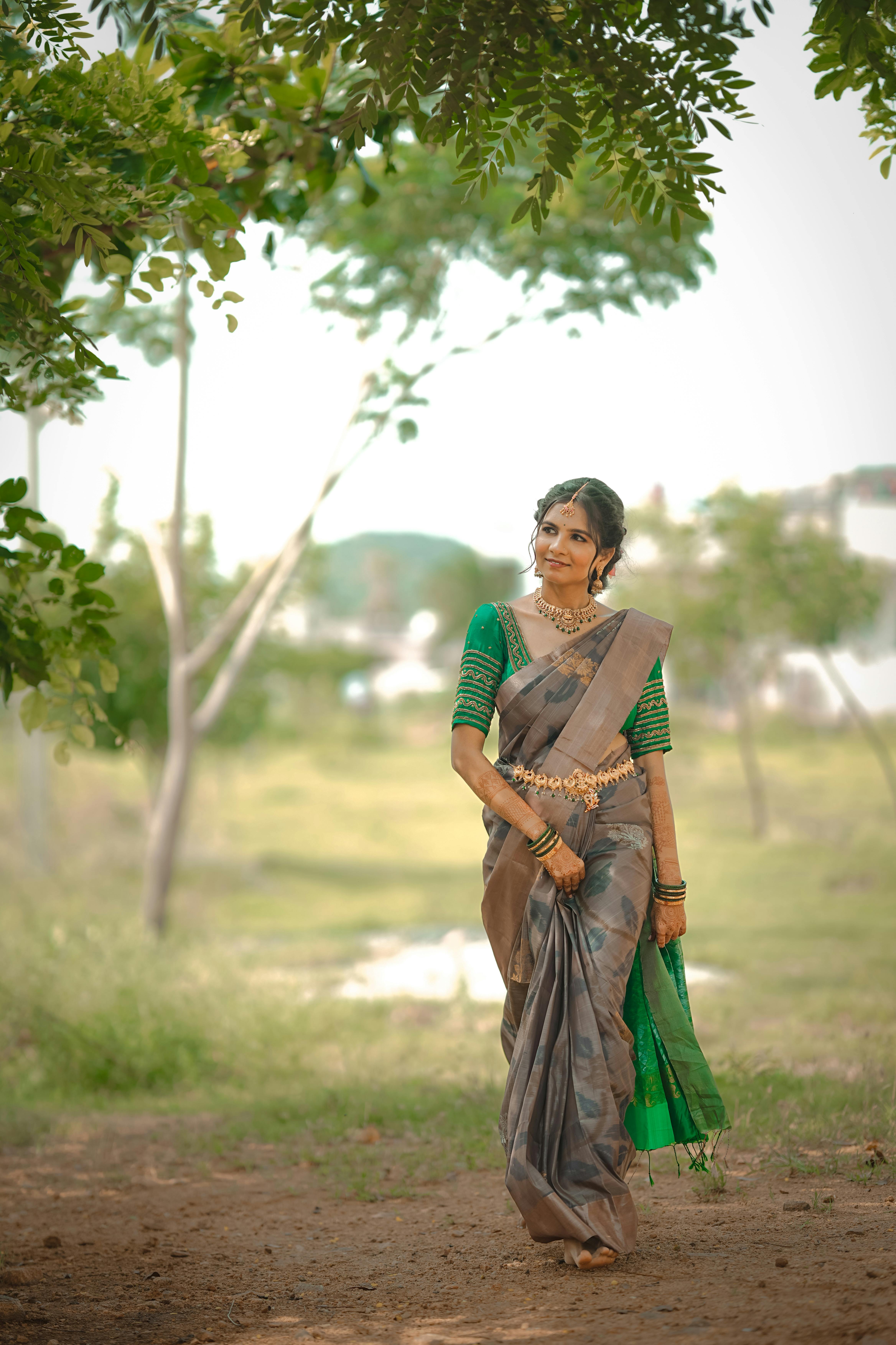 A woman in a green sari walking through a field · Free Stock Photo