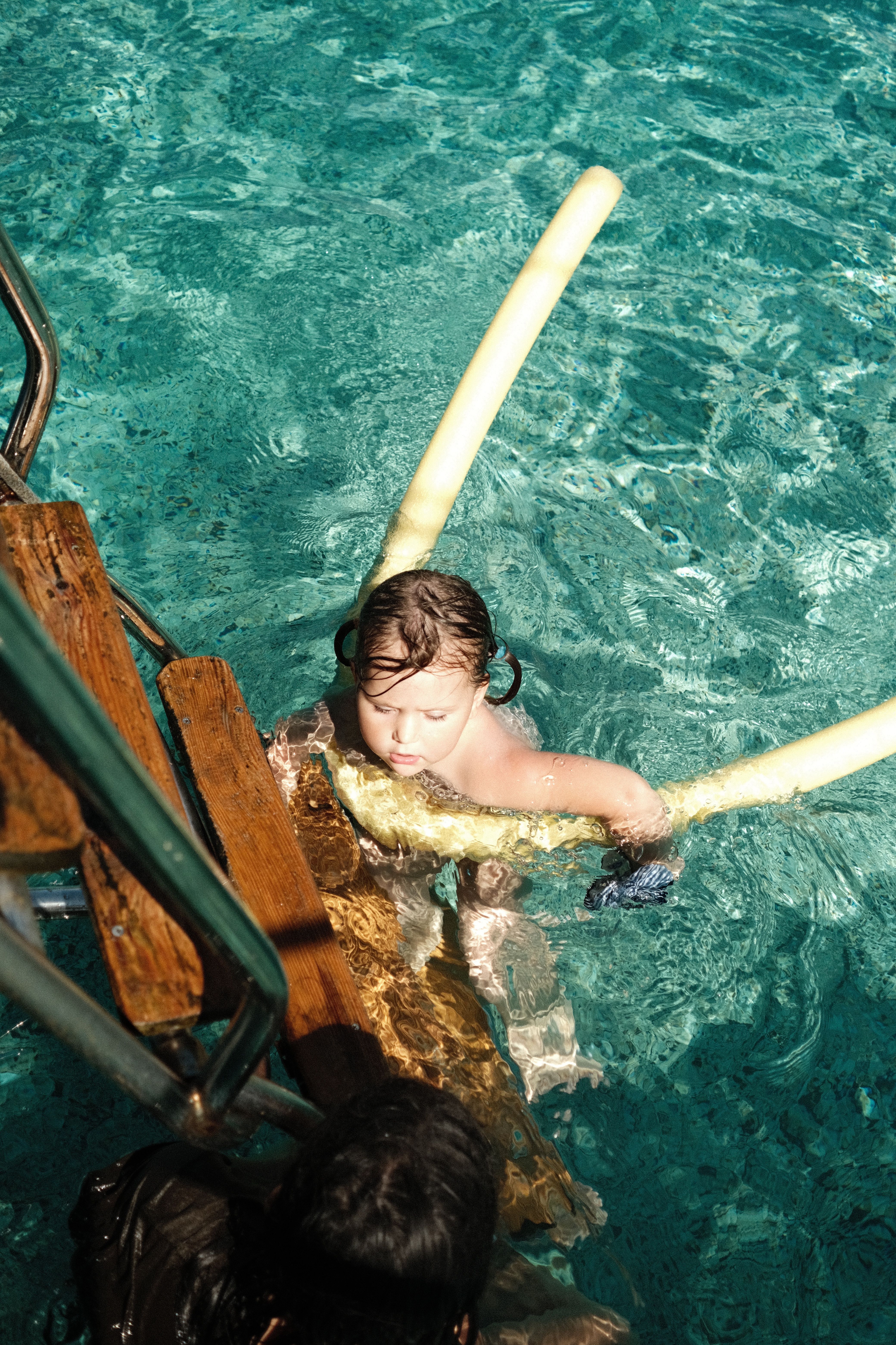 A child is swimming in the water with a yellow tube · Free Stock Photo