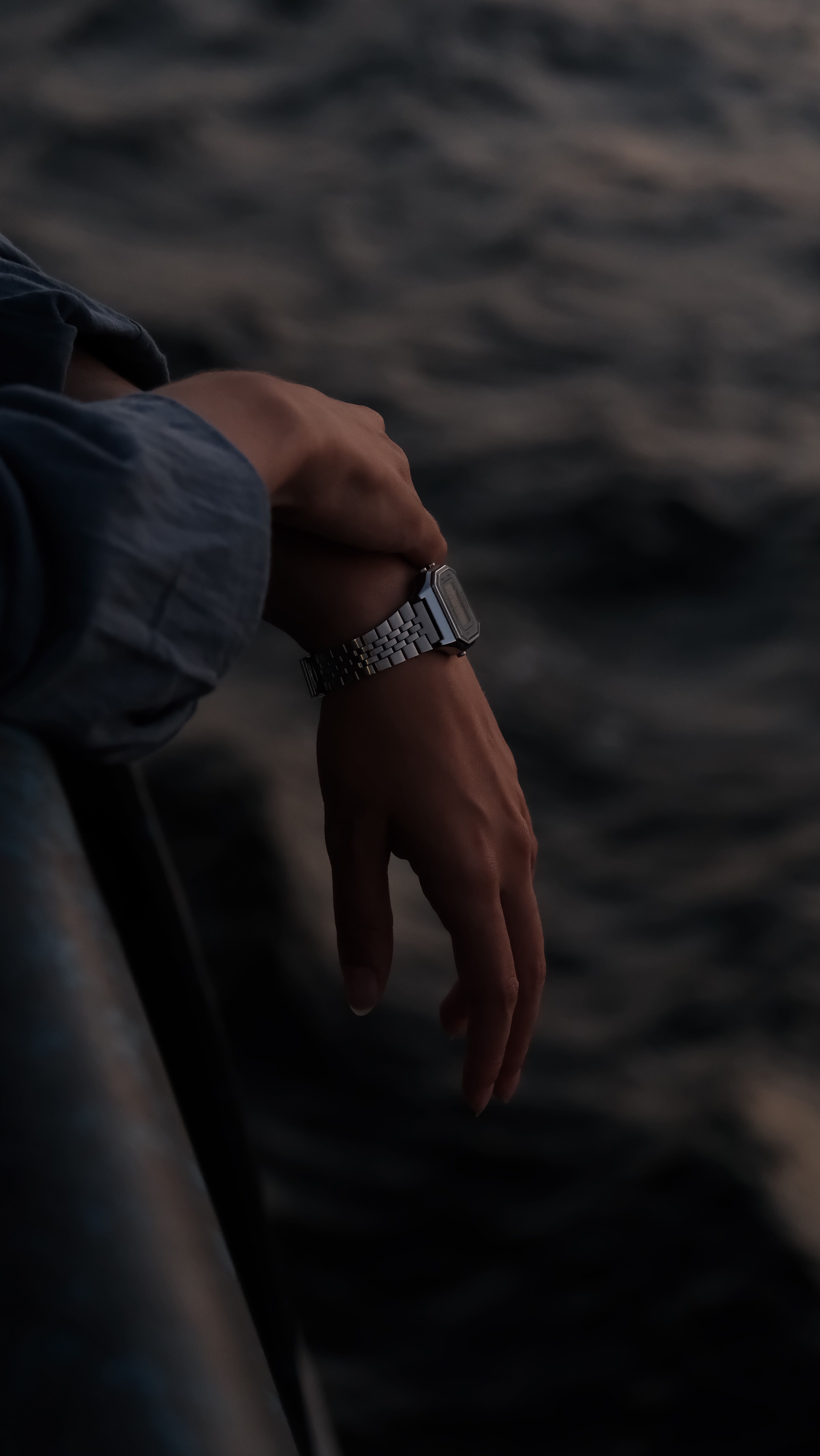 A person's hand is on a watch while standing on the edge of a boat ...
