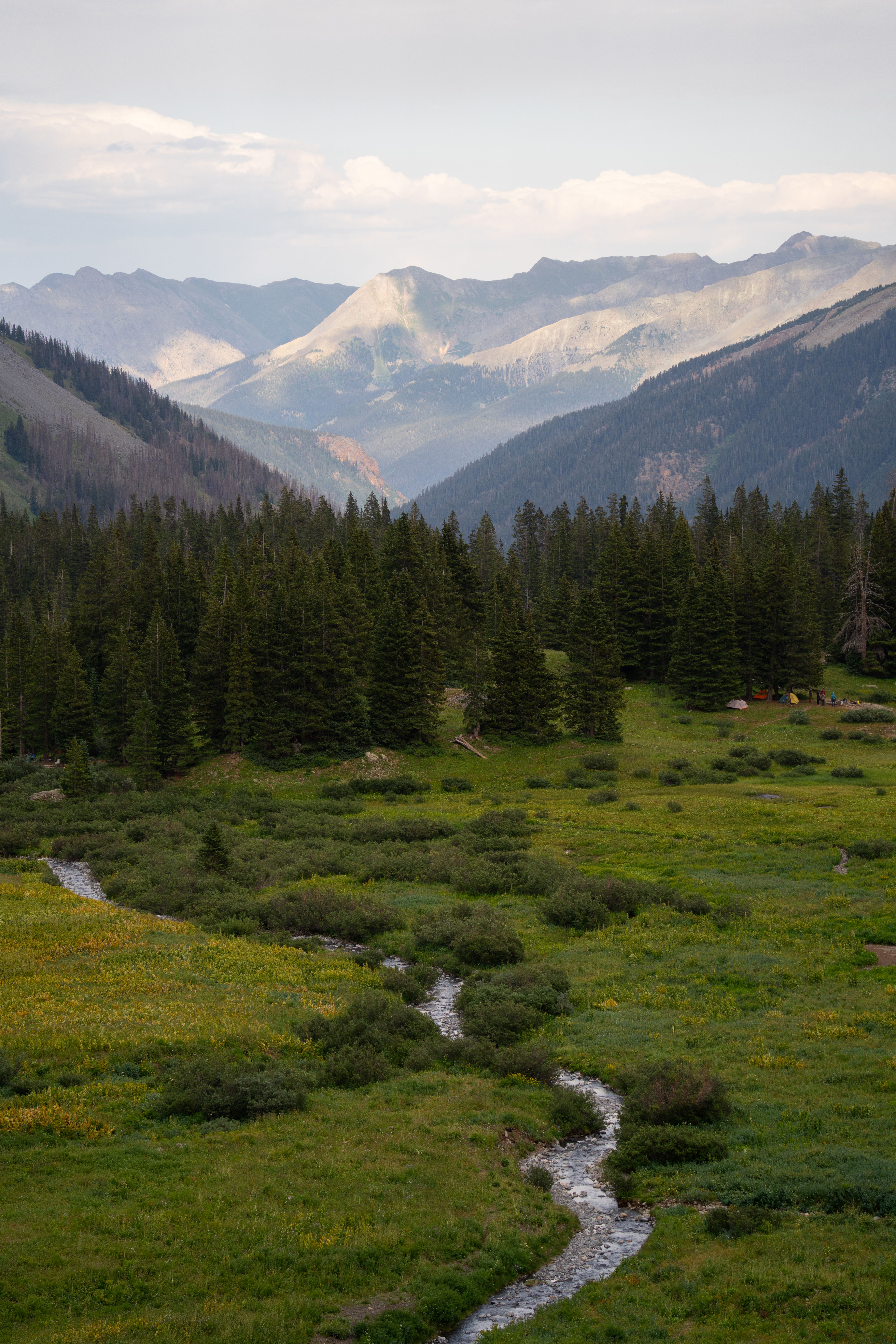 A stream runs through a valley with mountains in the background · Free ...