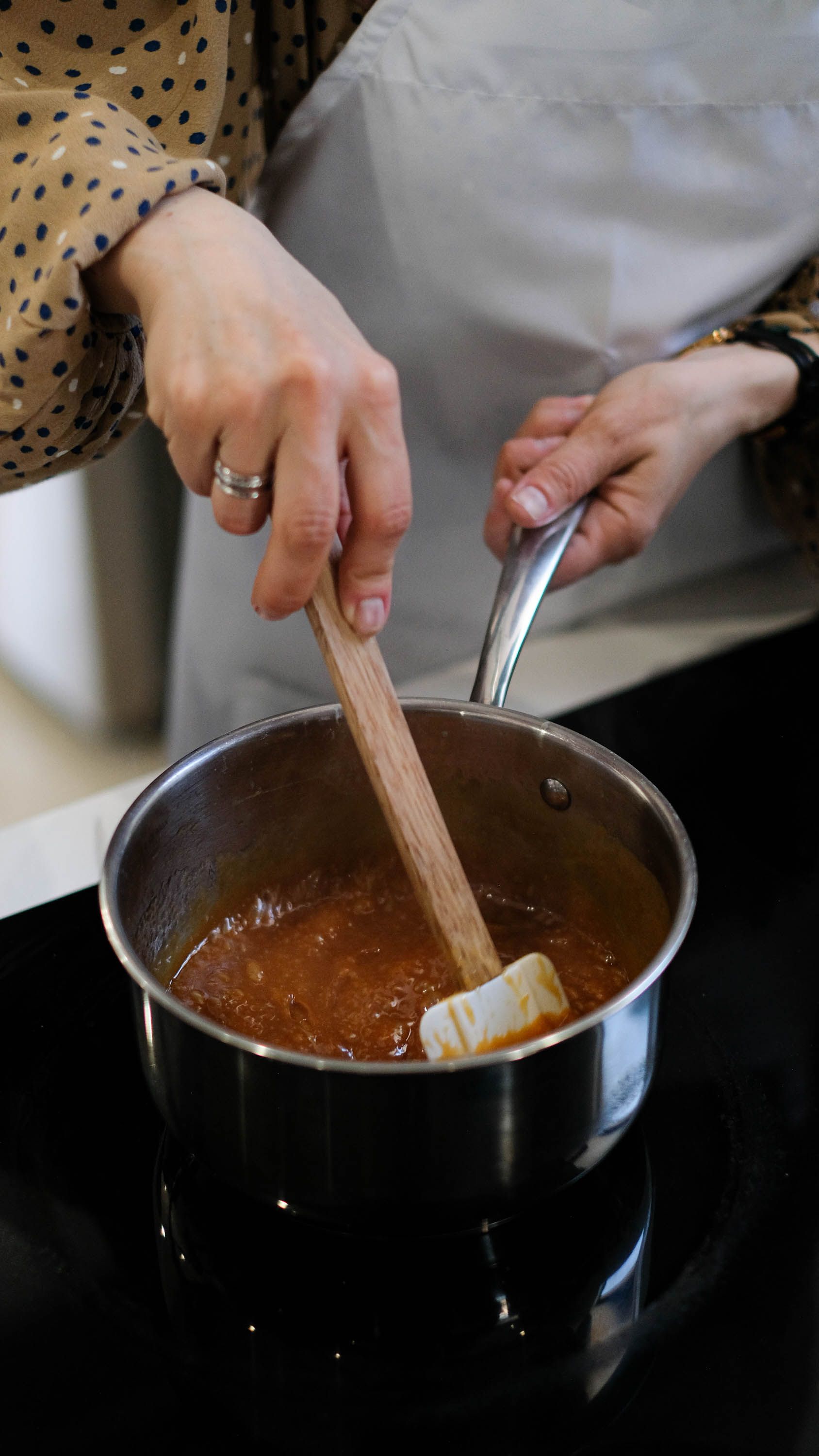 A woman stirring a saucepan with a wooden spoon · Free Stock Photo