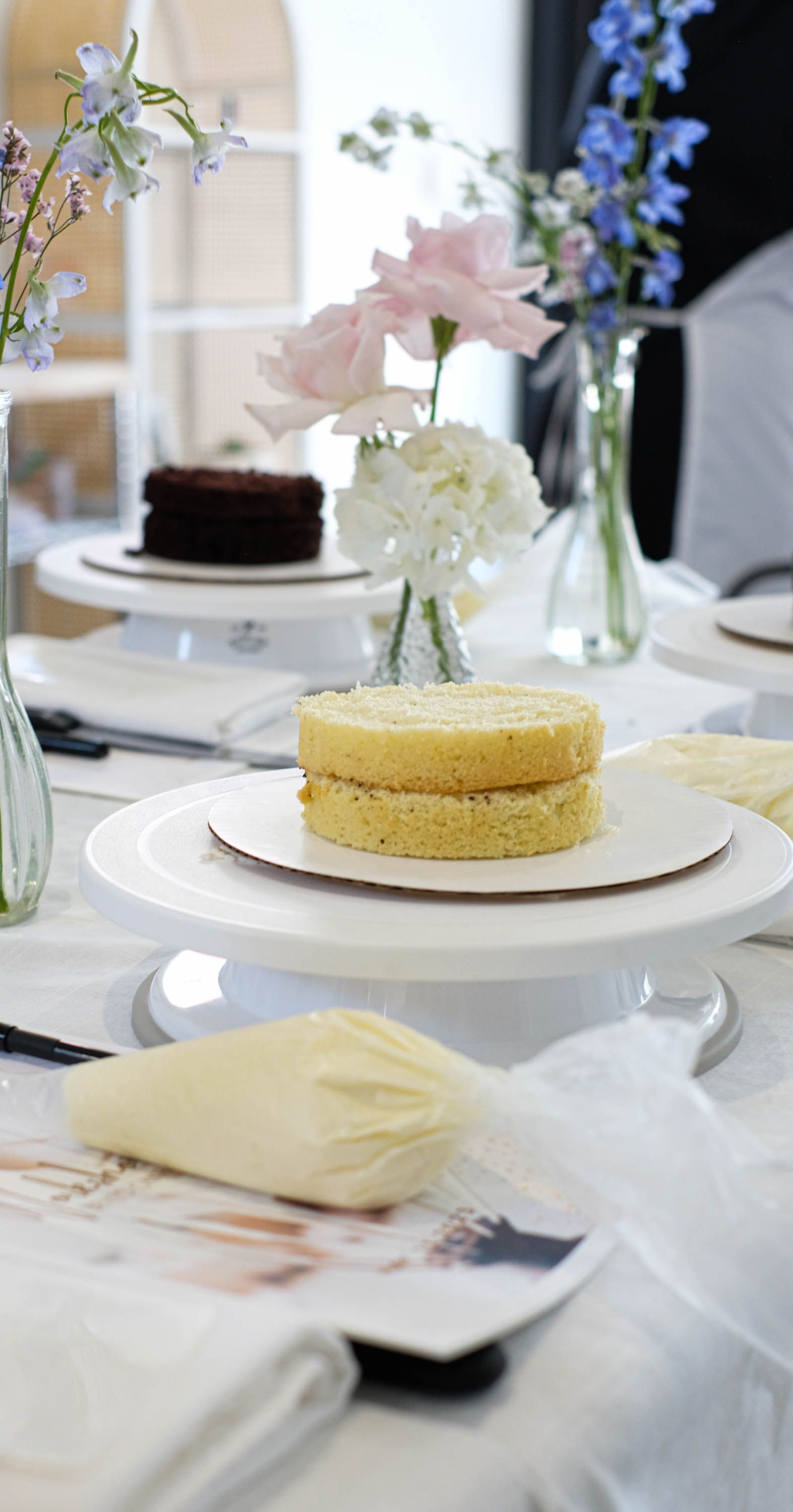 A cake is on a table with flowers and vases · Free Stock Photo