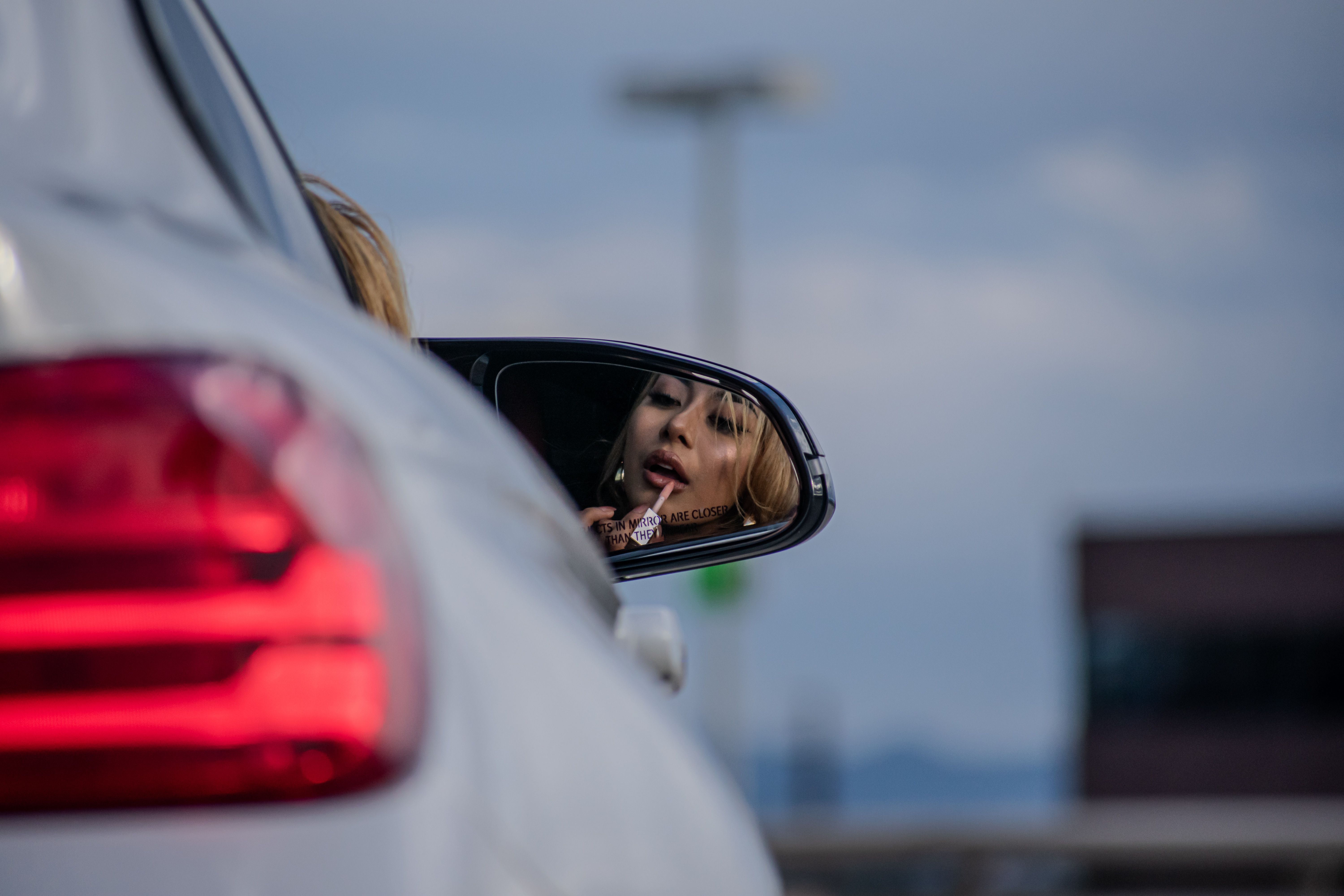 A woman is looking in the mirror of a car · Free Stock Photo