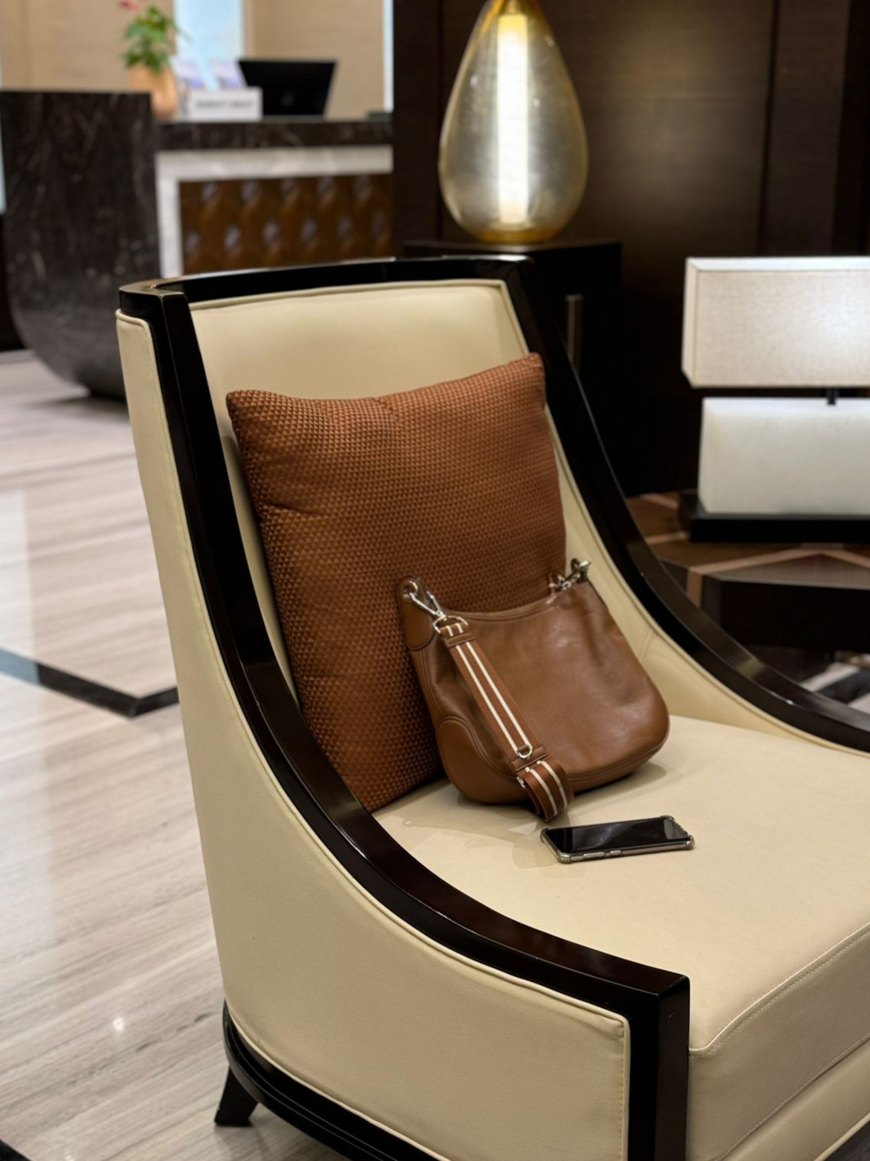 A brown purse sits on a chair in a hotel lobby · Free Stock Photo