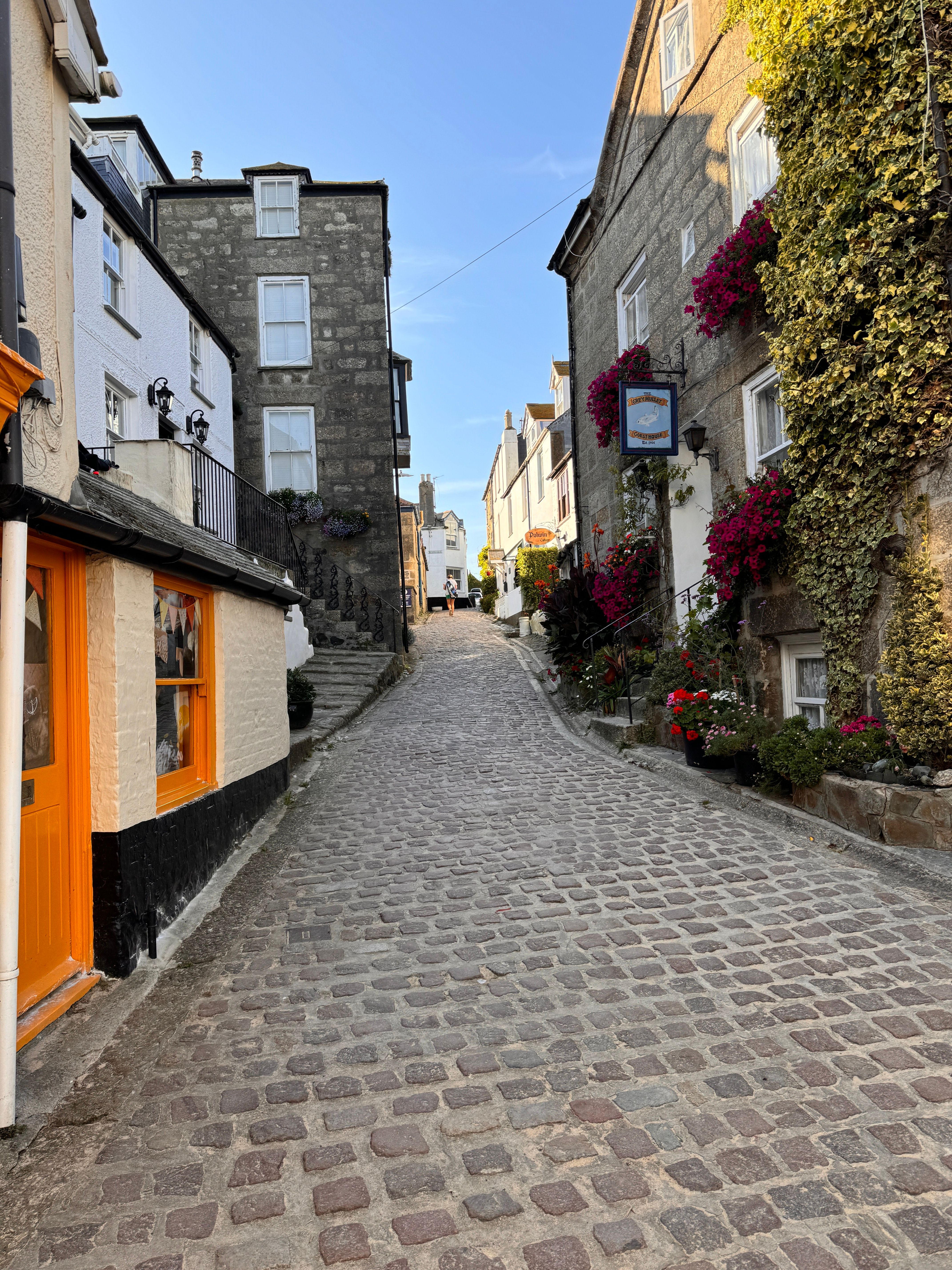 A cobblestone street with orange doors and a building · Free Stock Photo