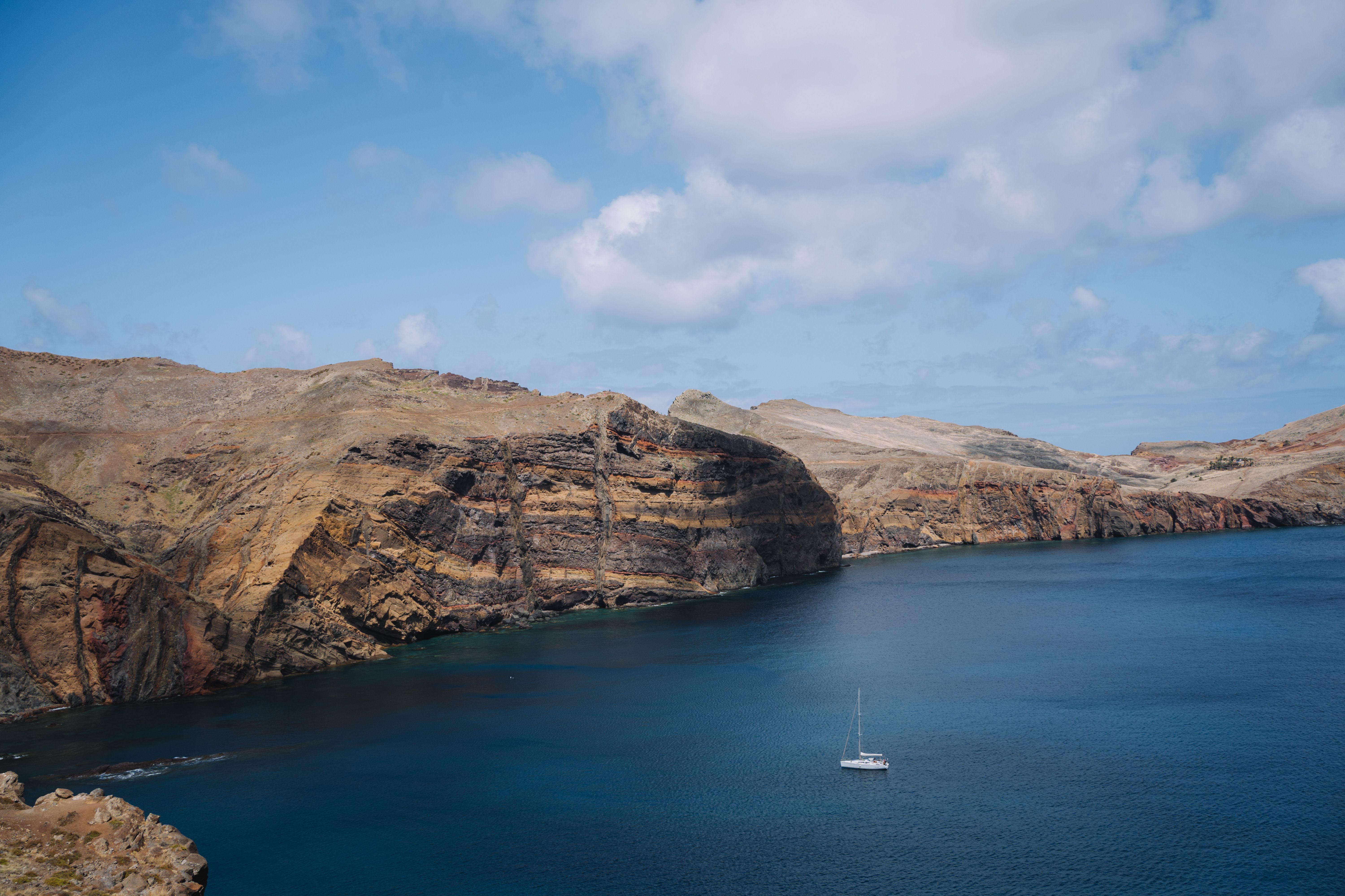 A boat sailing in the ocean near a rocky cliff · Free Stock Photo