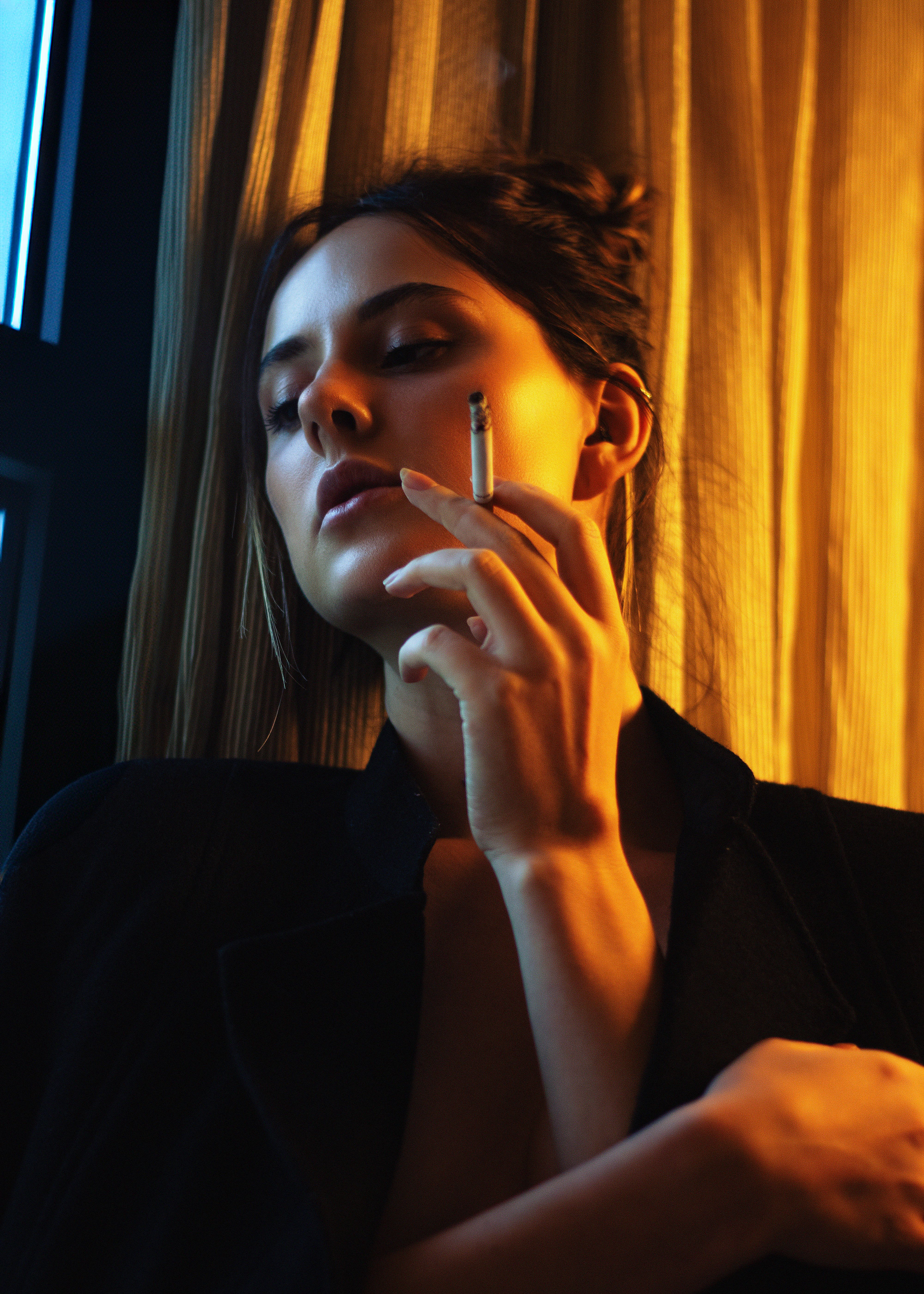 A woman smoking a cigarette in front of a window · Free Stock Photo