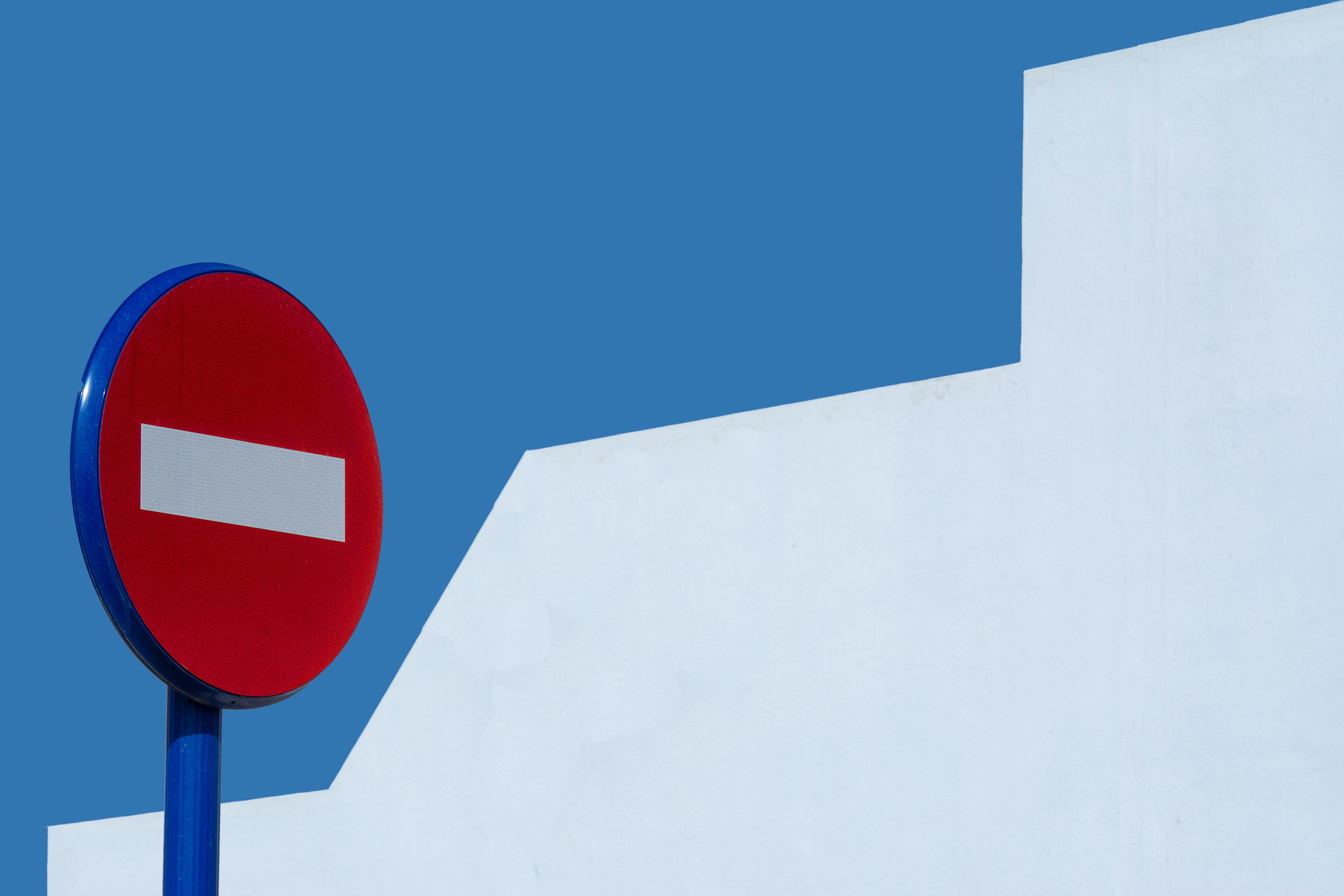 A red and blue no entry sign against a white wall · Free Stock Photo