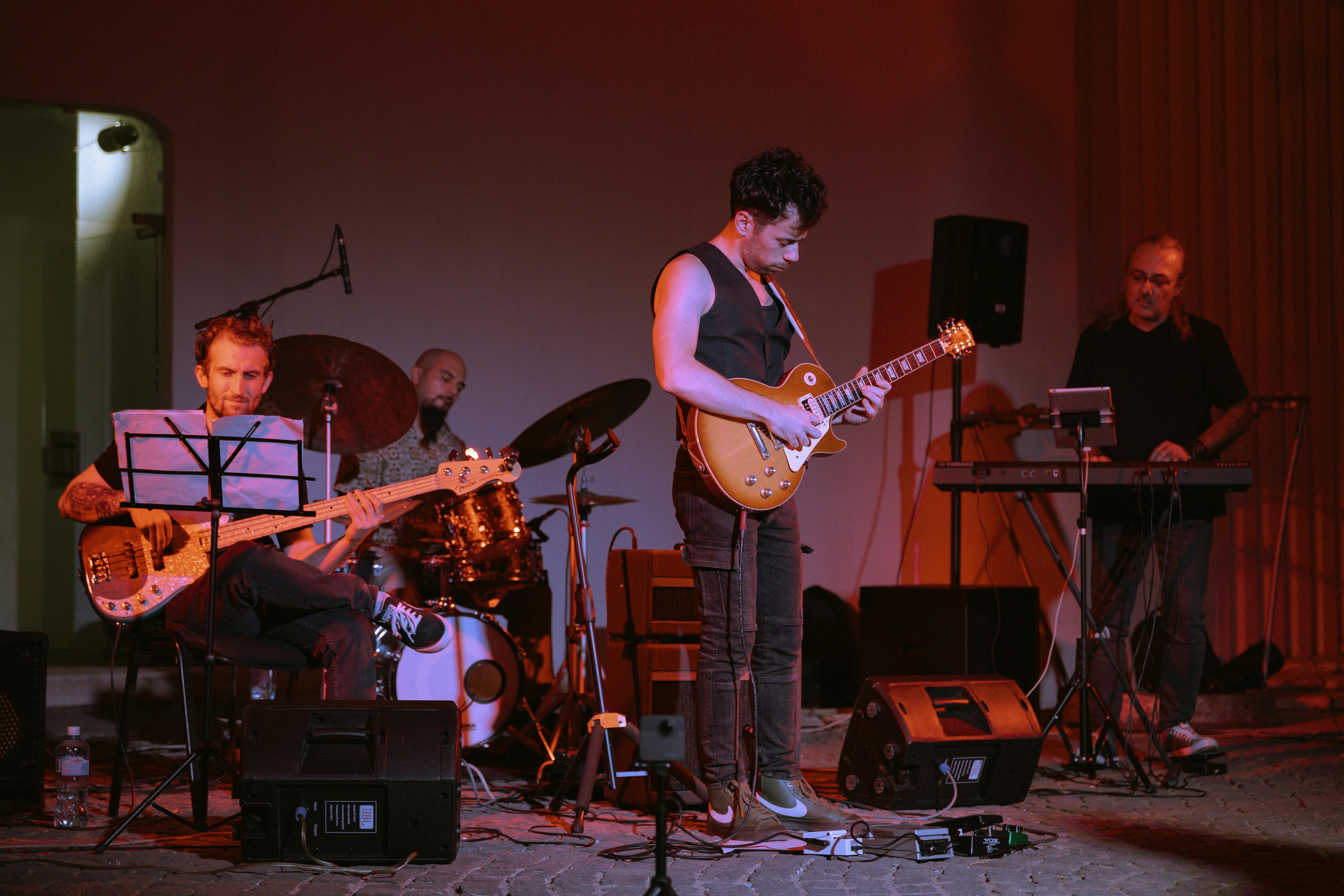 A band playing music in a room with red lights · Free Stock Photo