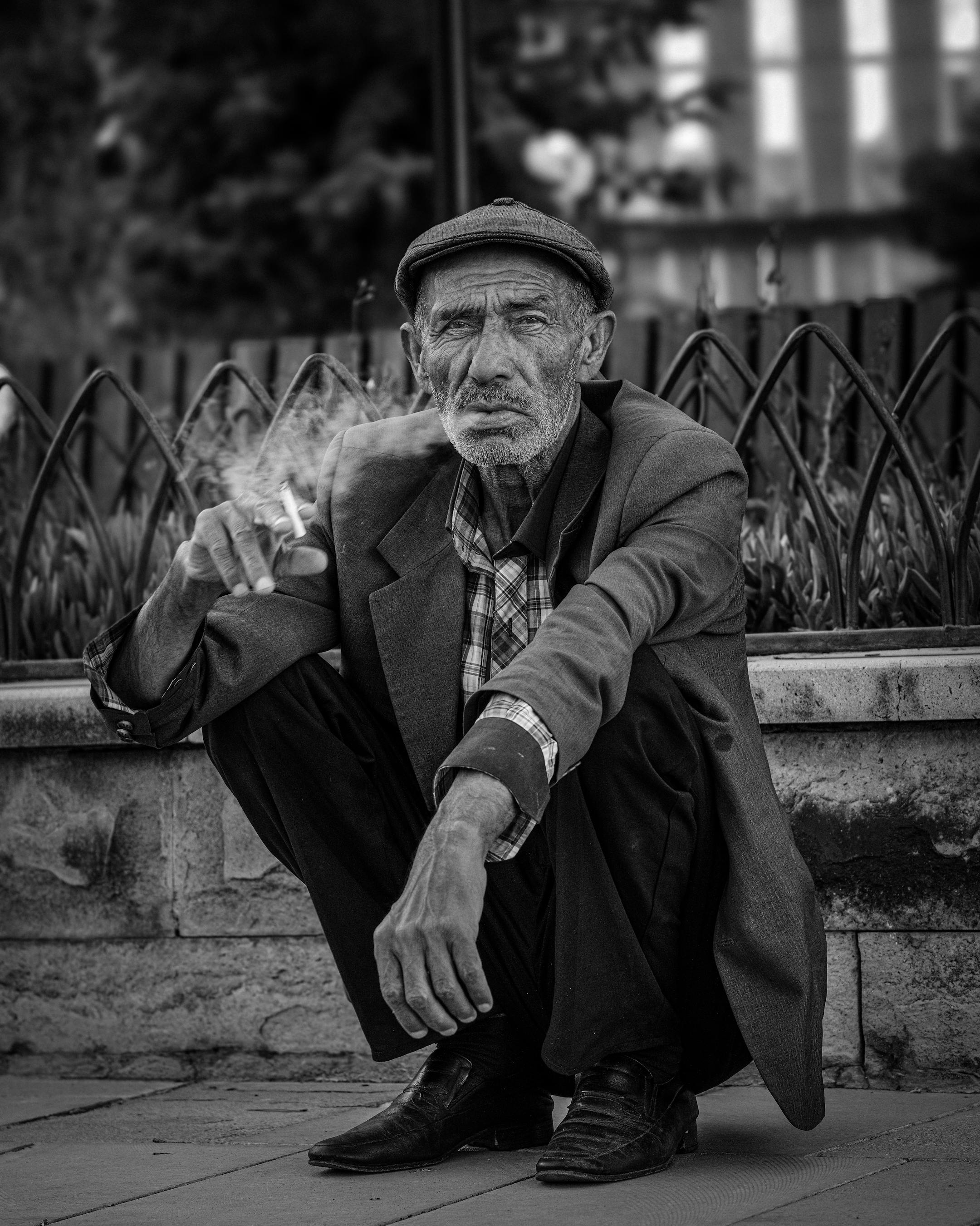 A man sitting on the ground smoking a cigarette · Free Stock Photo