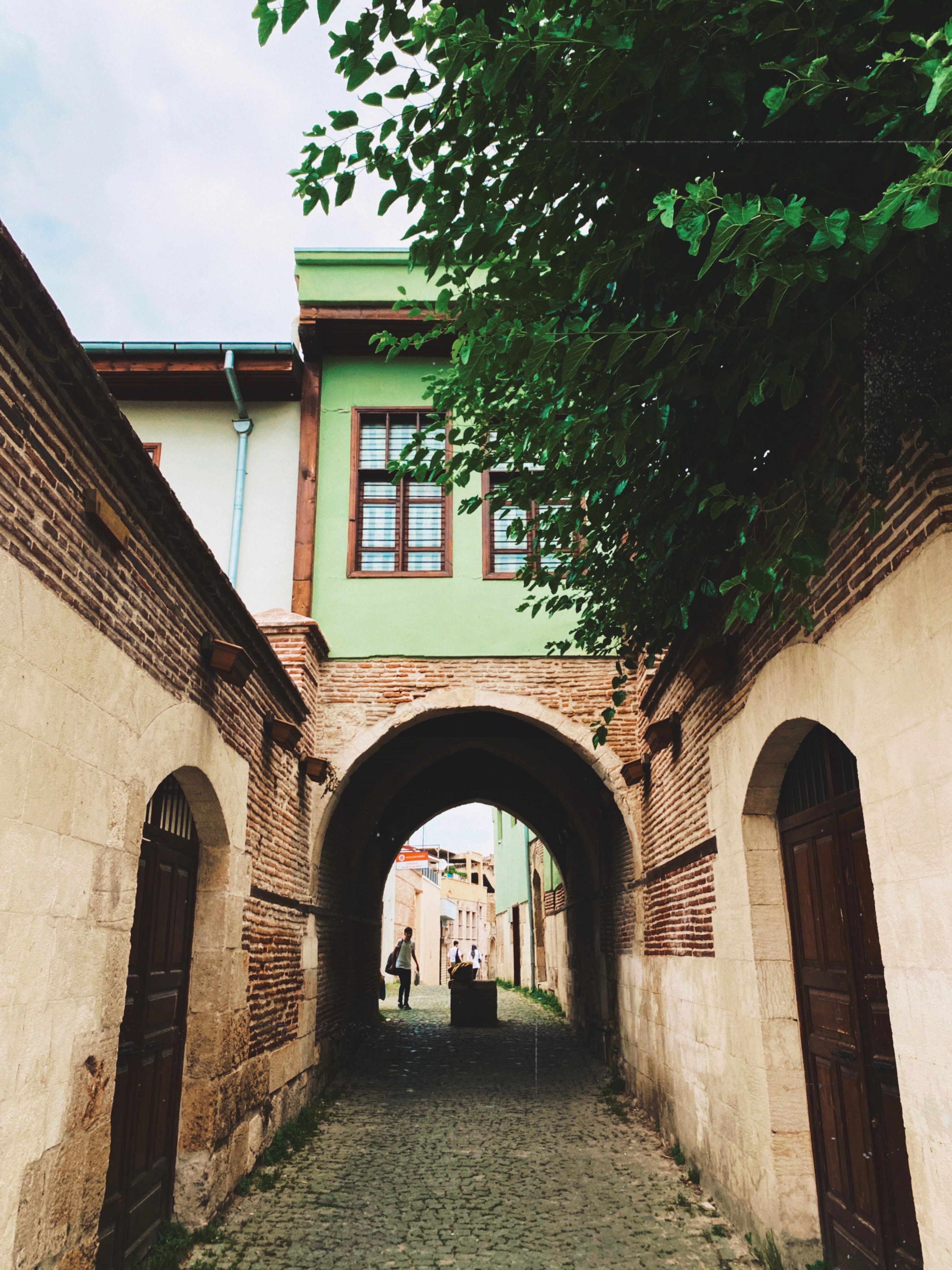 A narrow alleyway with a green door and a green building · Free Stock Photo