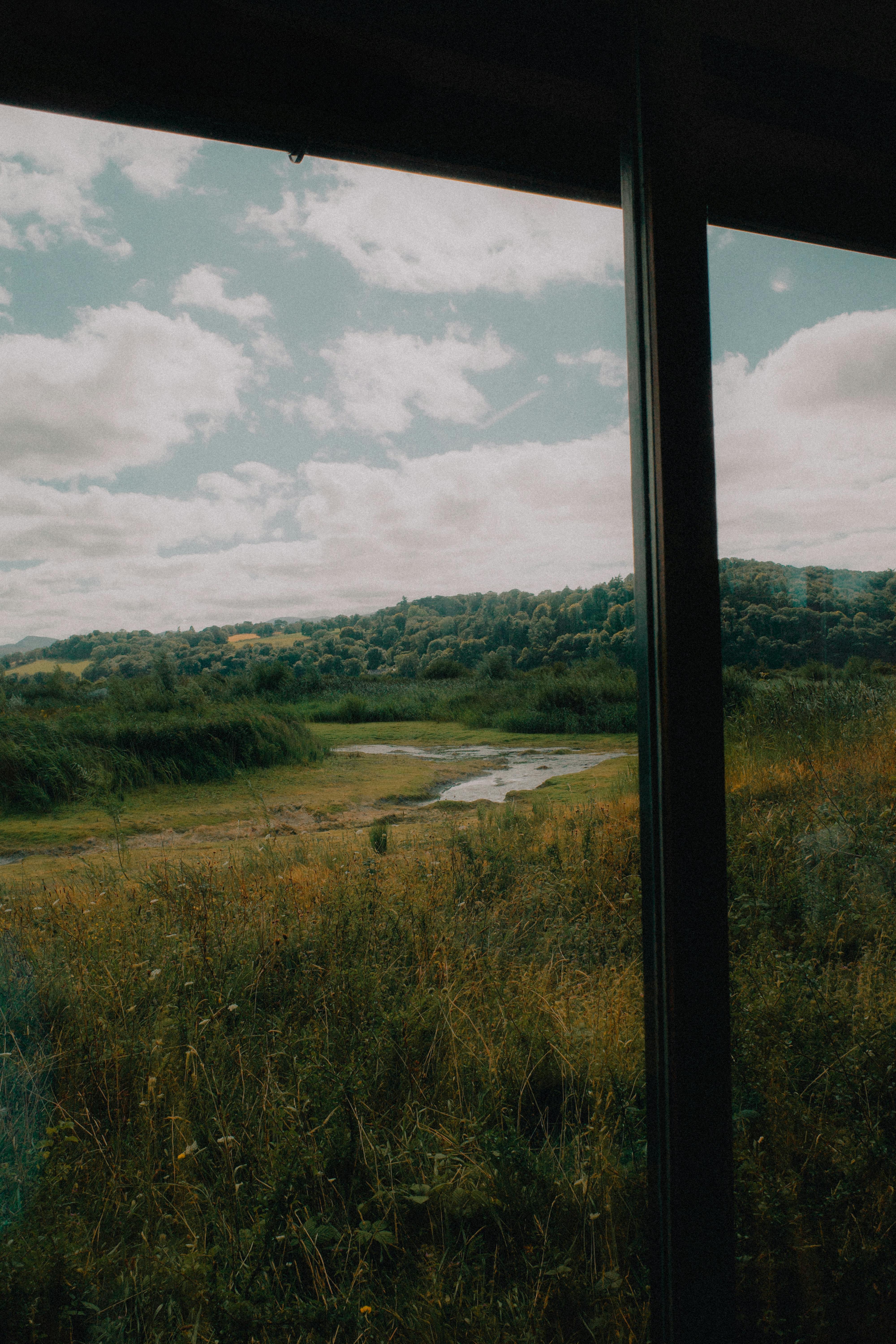 A view of a river and grassland from inside a window · Free Stock Photo