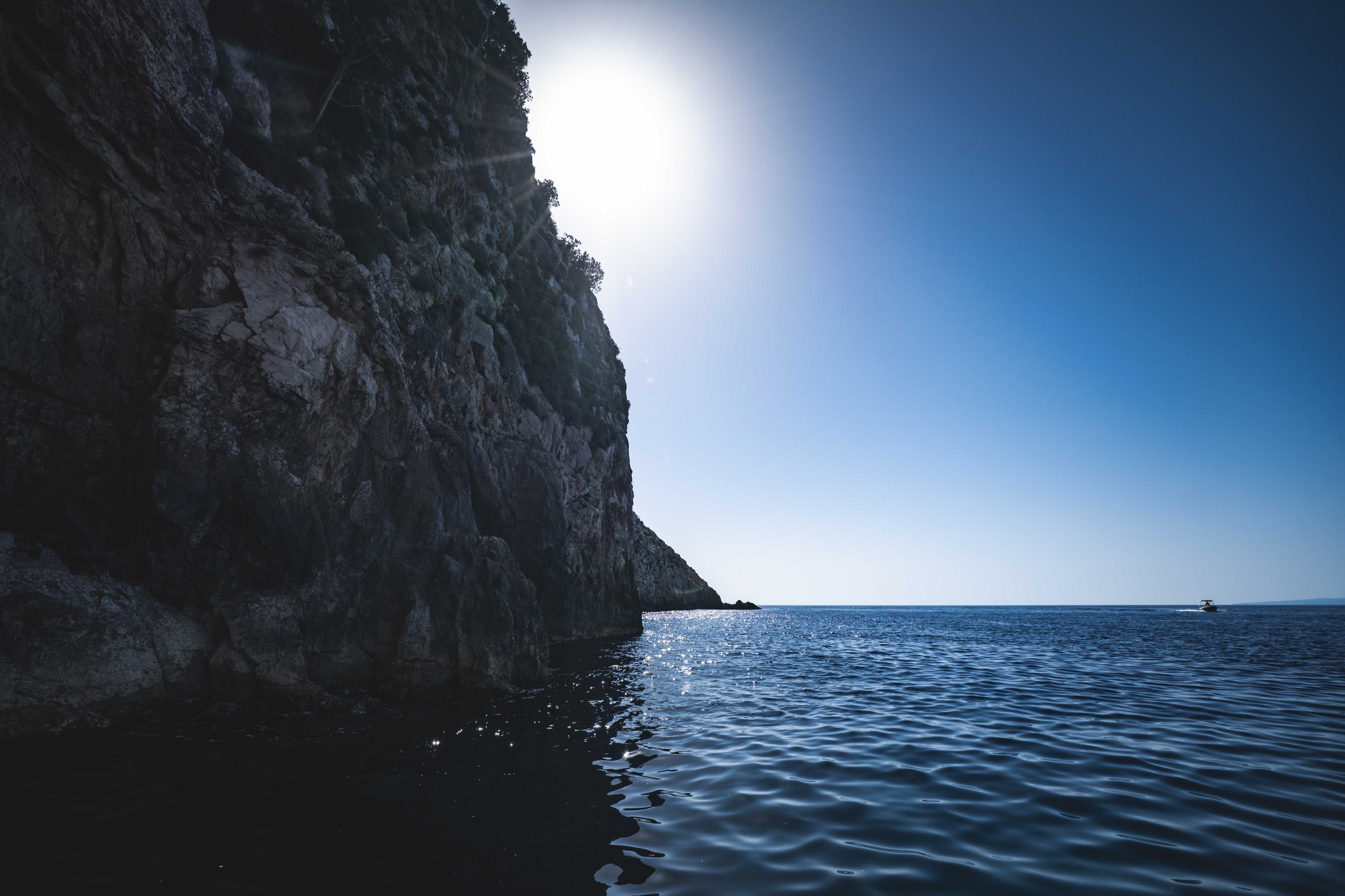 A boat is sailing in the ocean near a cliff · Free Stock Photo