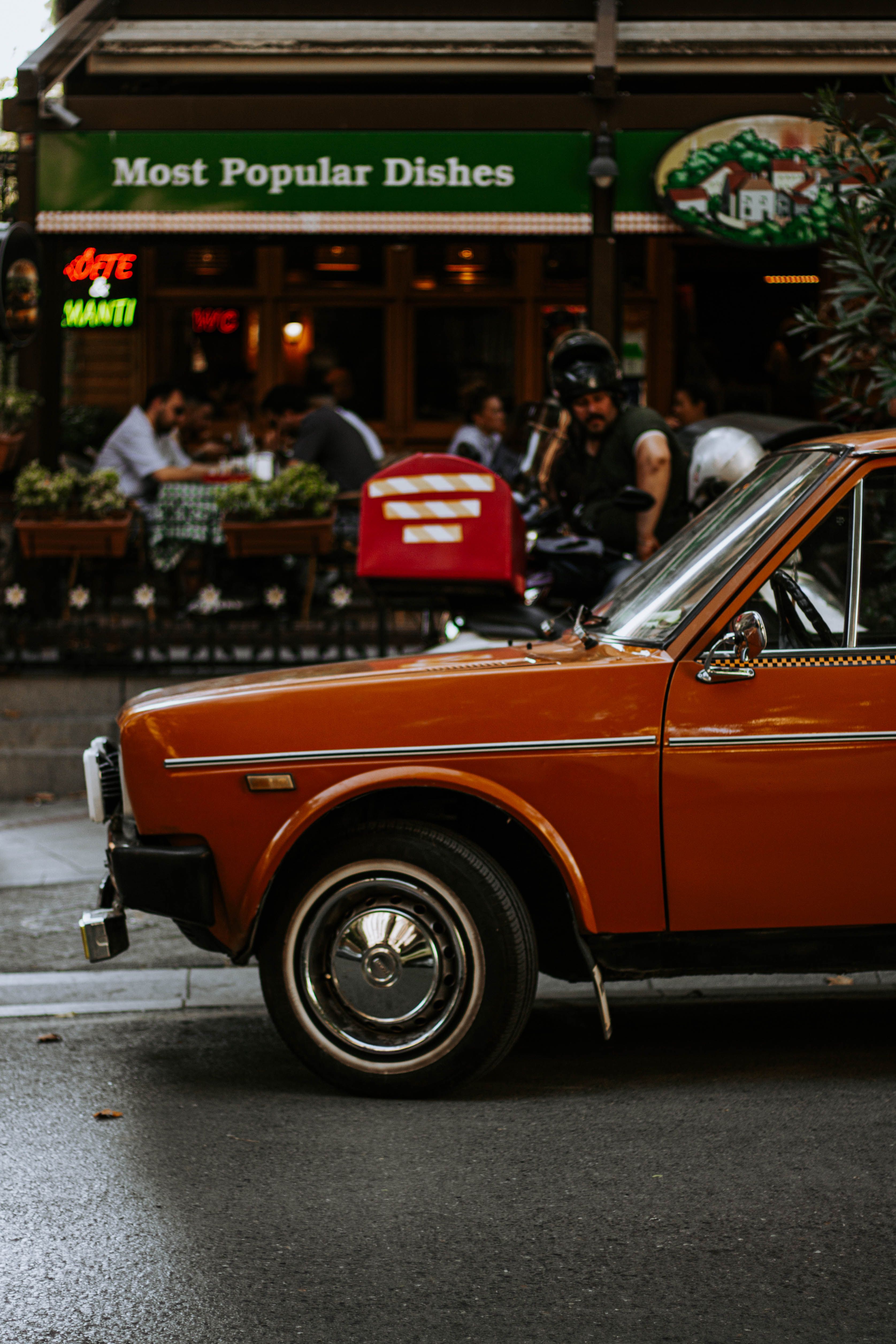 An orange car parked in front of a restaurant · Free Stock Photo