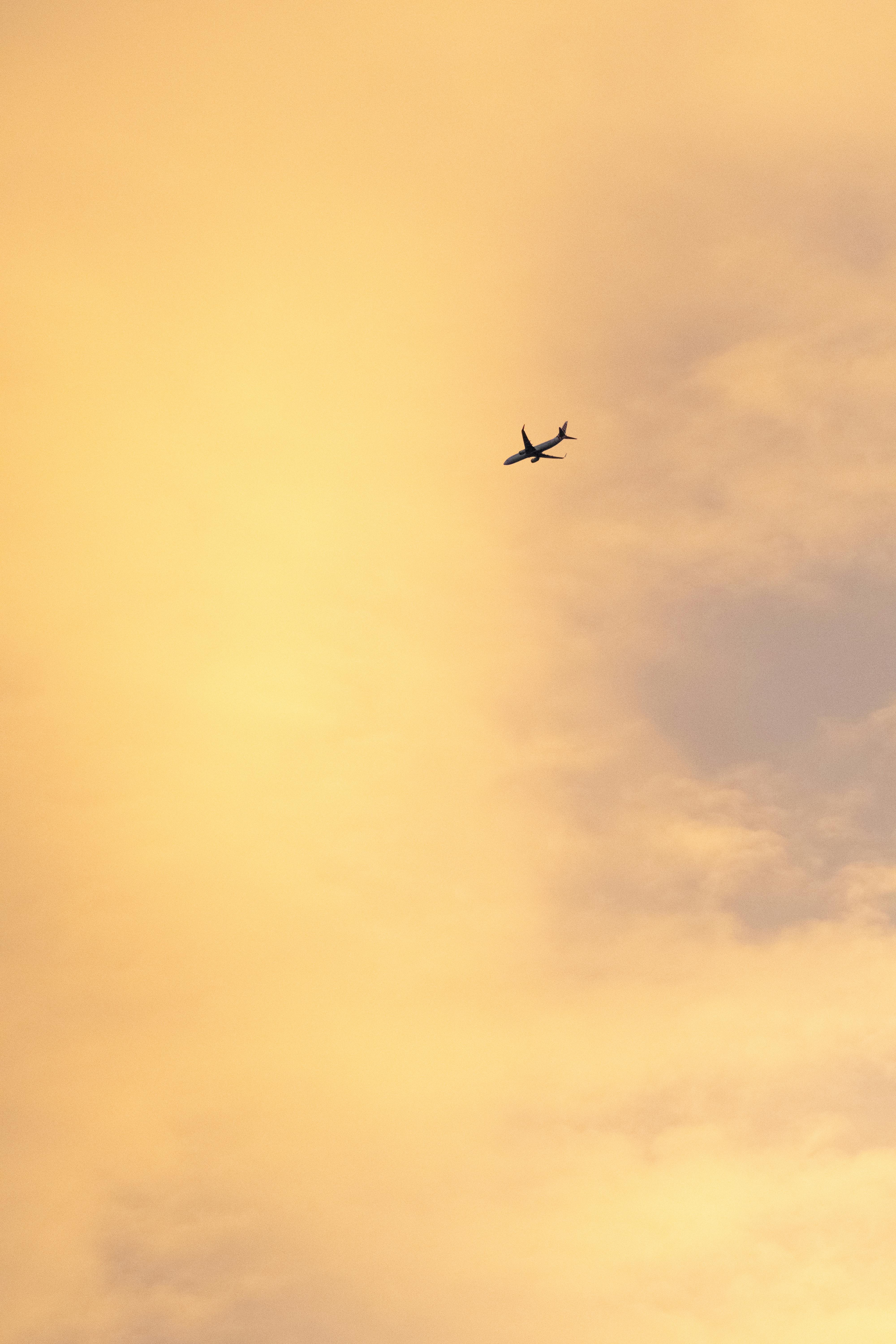A plane flying through the sky in a cloudy sky · Free Stock Photo