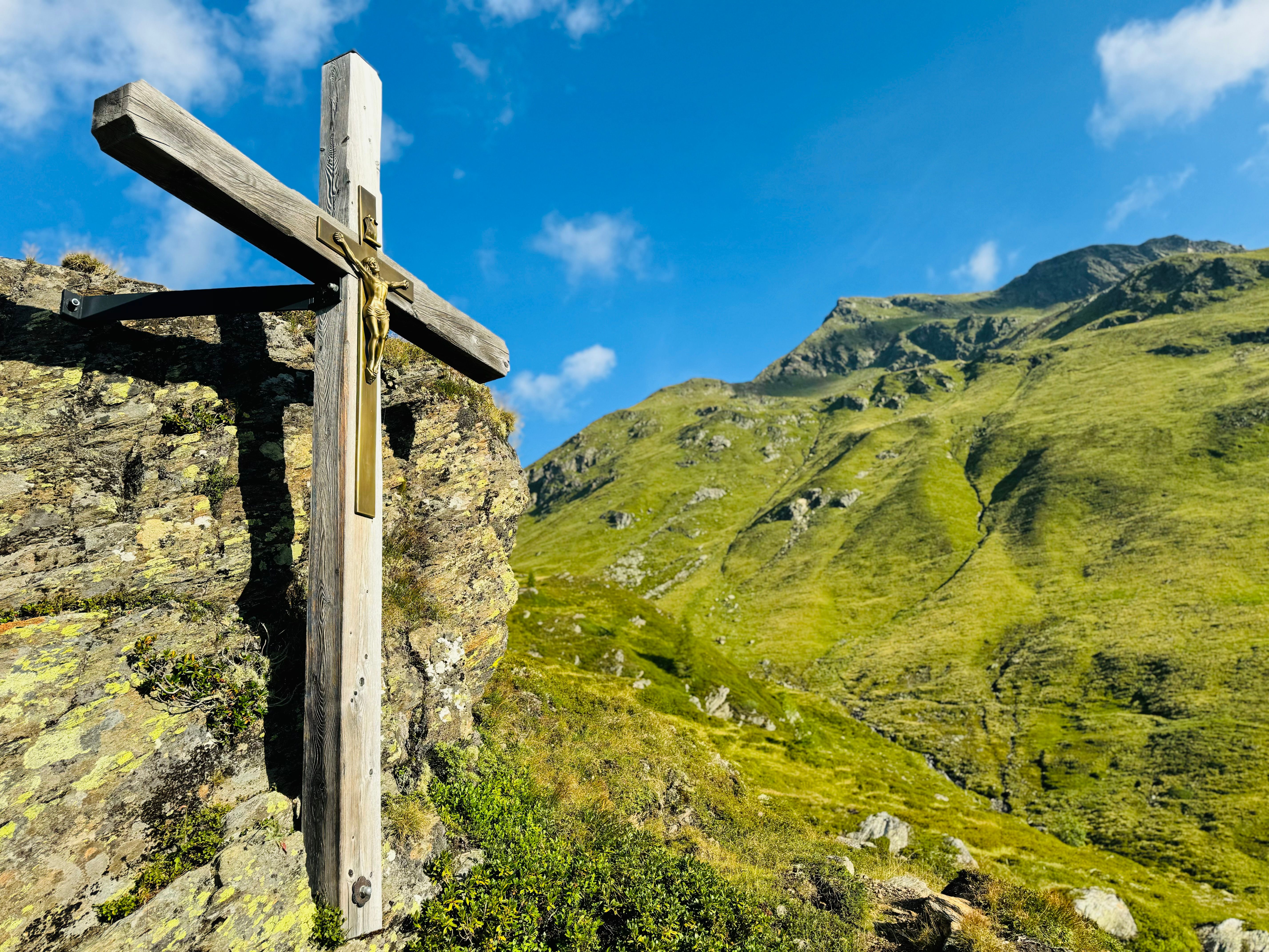 A wooden cross on a hillside with mountains in the background · Free ...