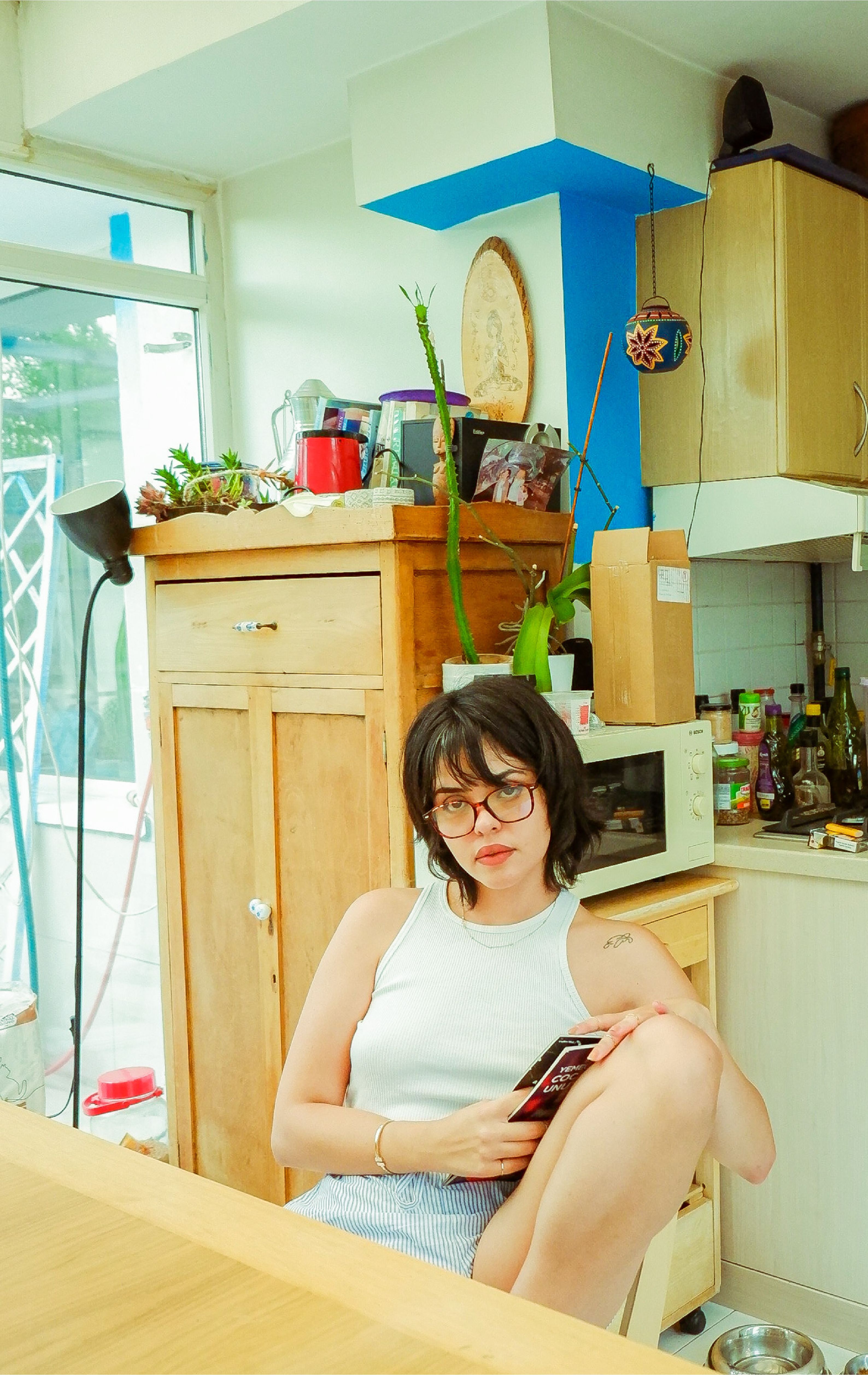 A woman sitting on a kitchen counter holding a cell phone · Free Stock ...