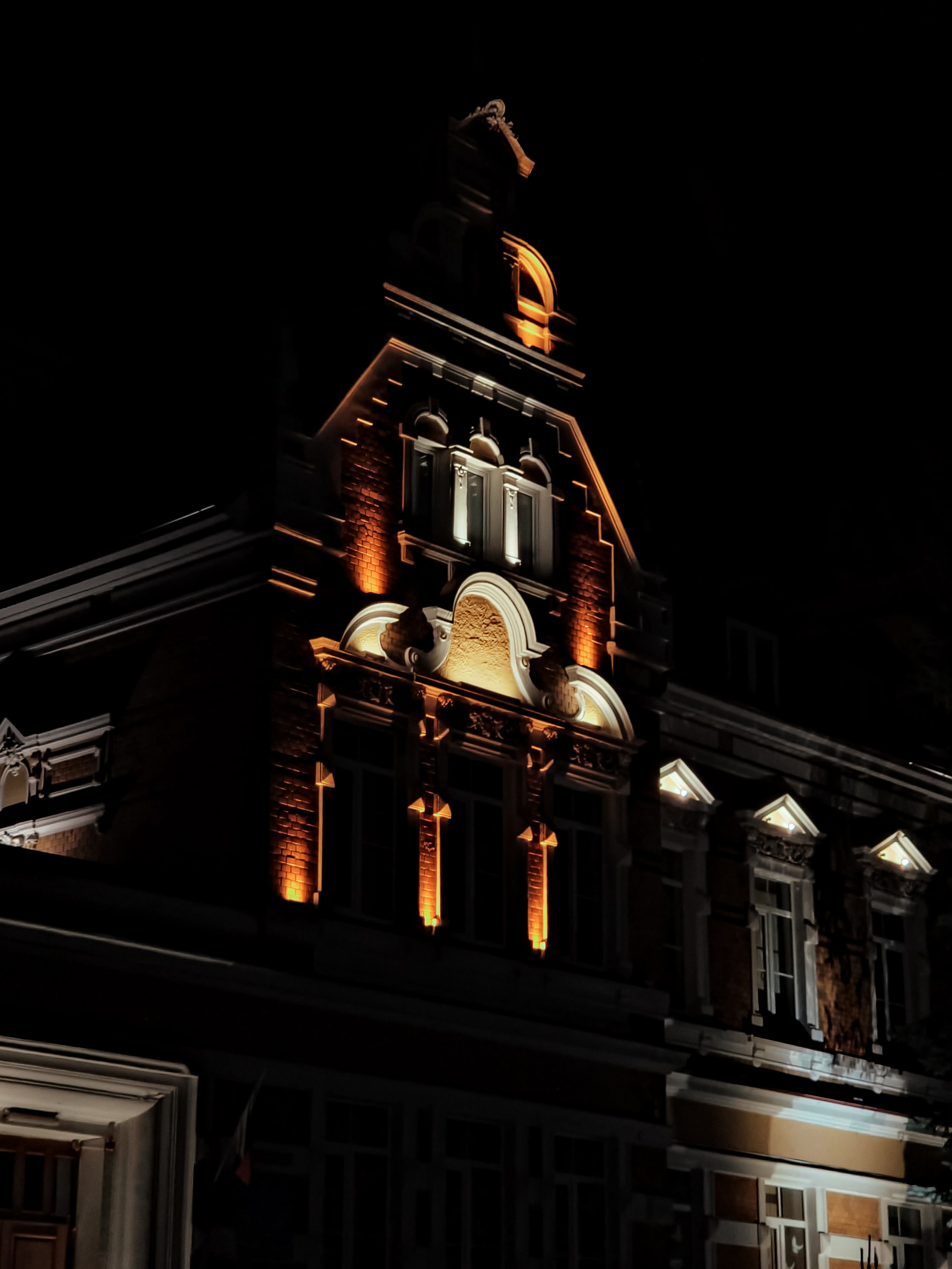 A building lit up at night with a clock tower · Free Stock Photo