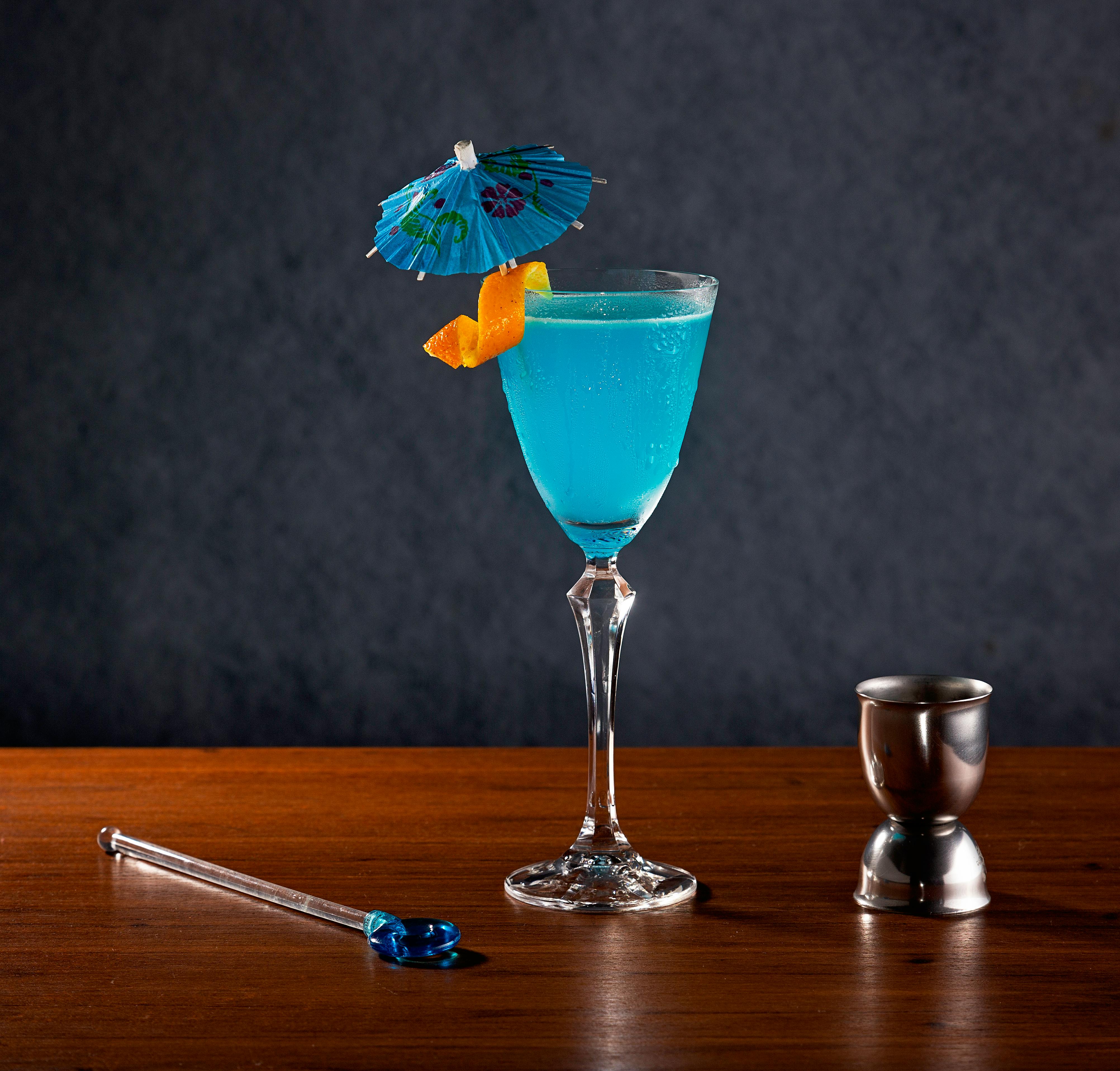 A blue cocktail with an umbrella and a spoon · Free Stock Photo