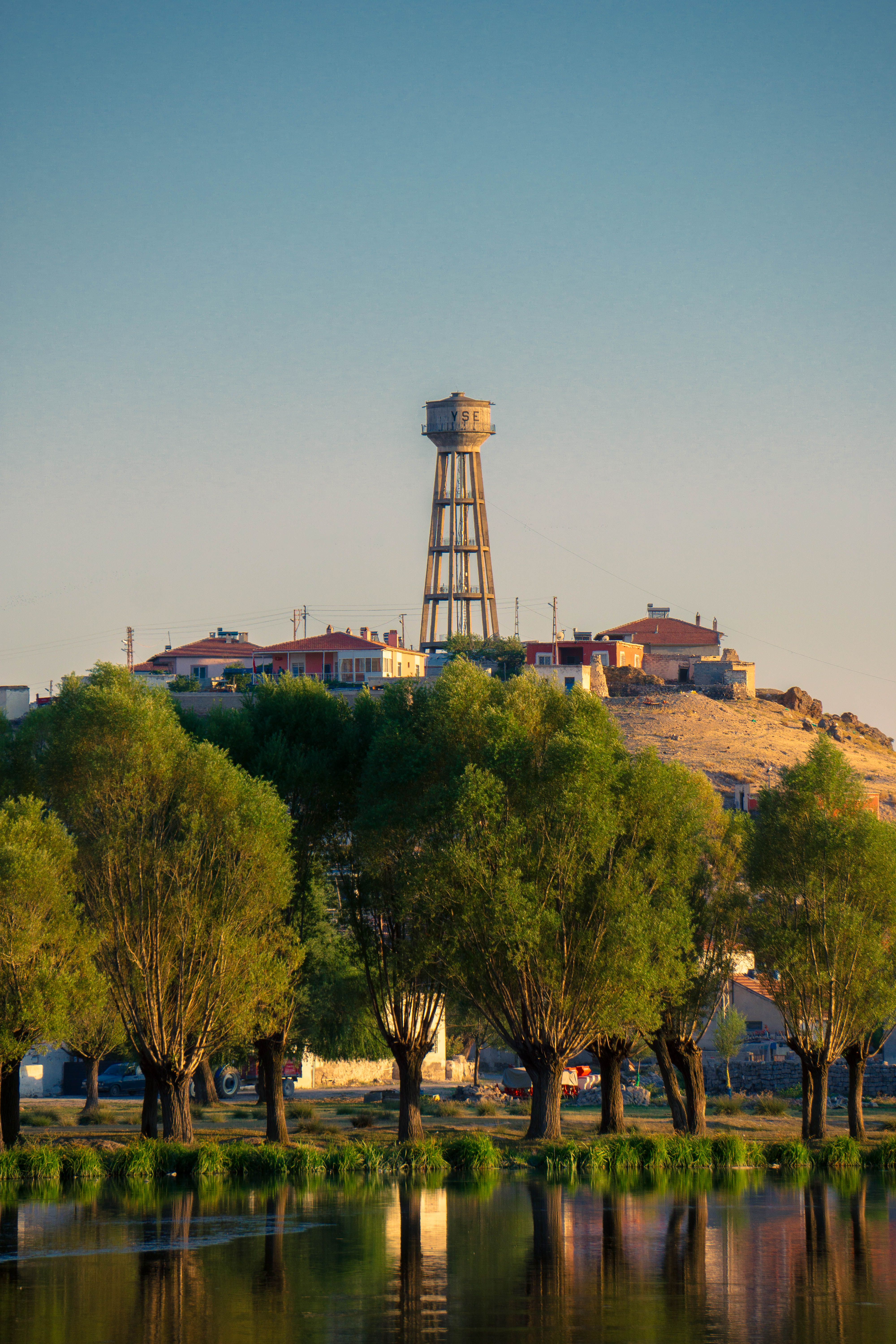A water tower sits on top of a hill next to trees · Free Stock Photo