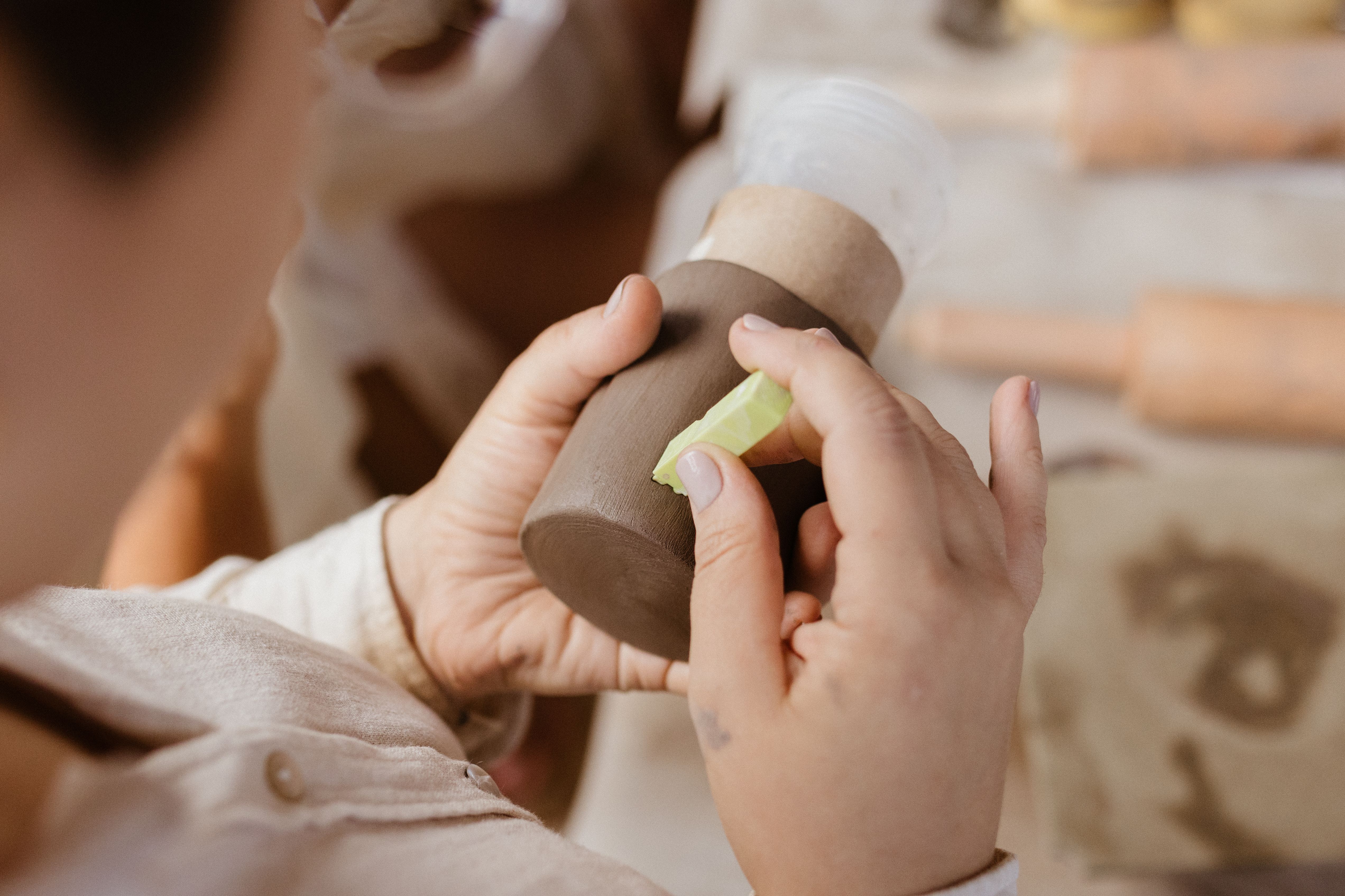 A person is making a clay pot with a brush · Free Stock Photo