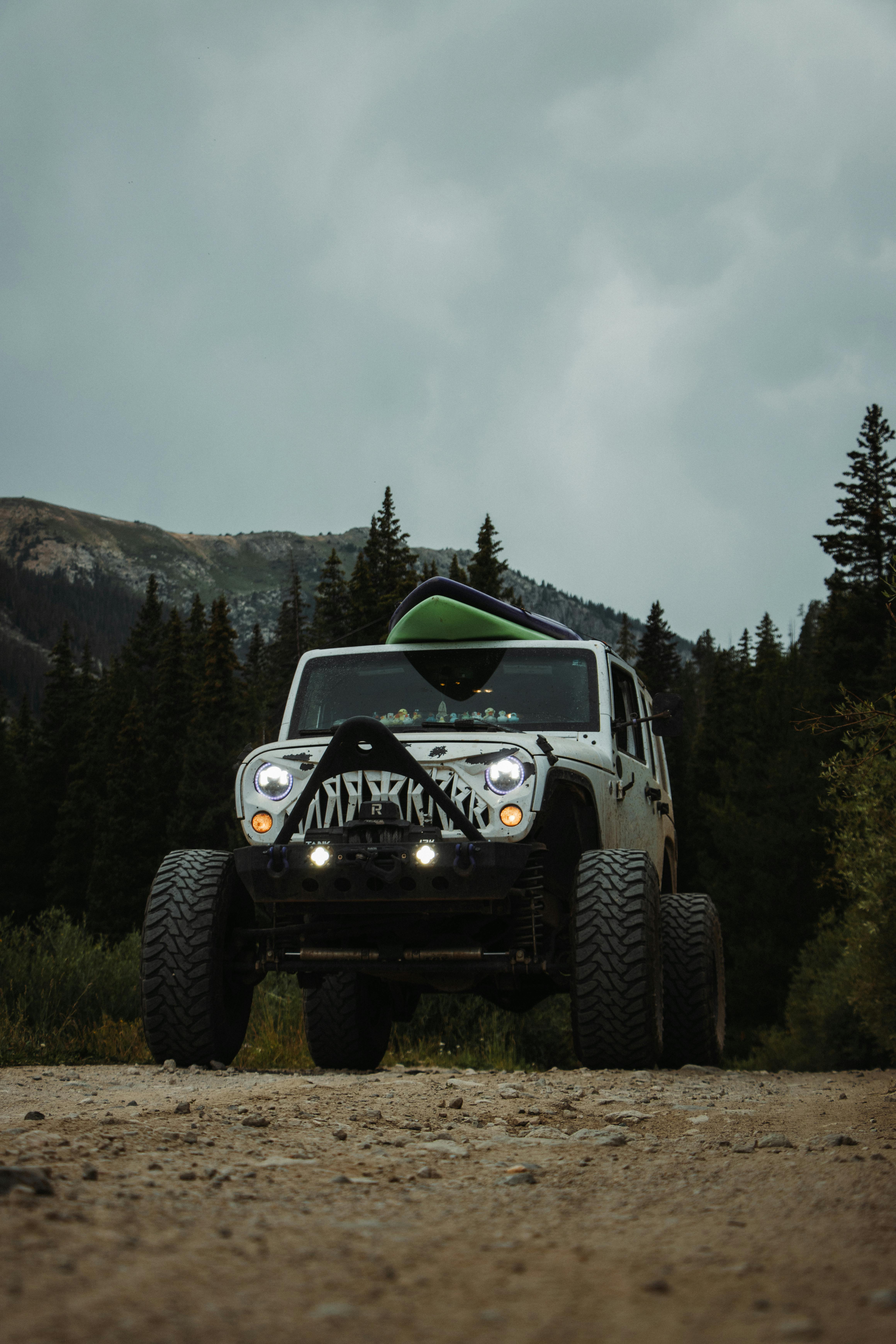 A jeep with a surfboard on top is driving down a dirt road · Free Stock ...