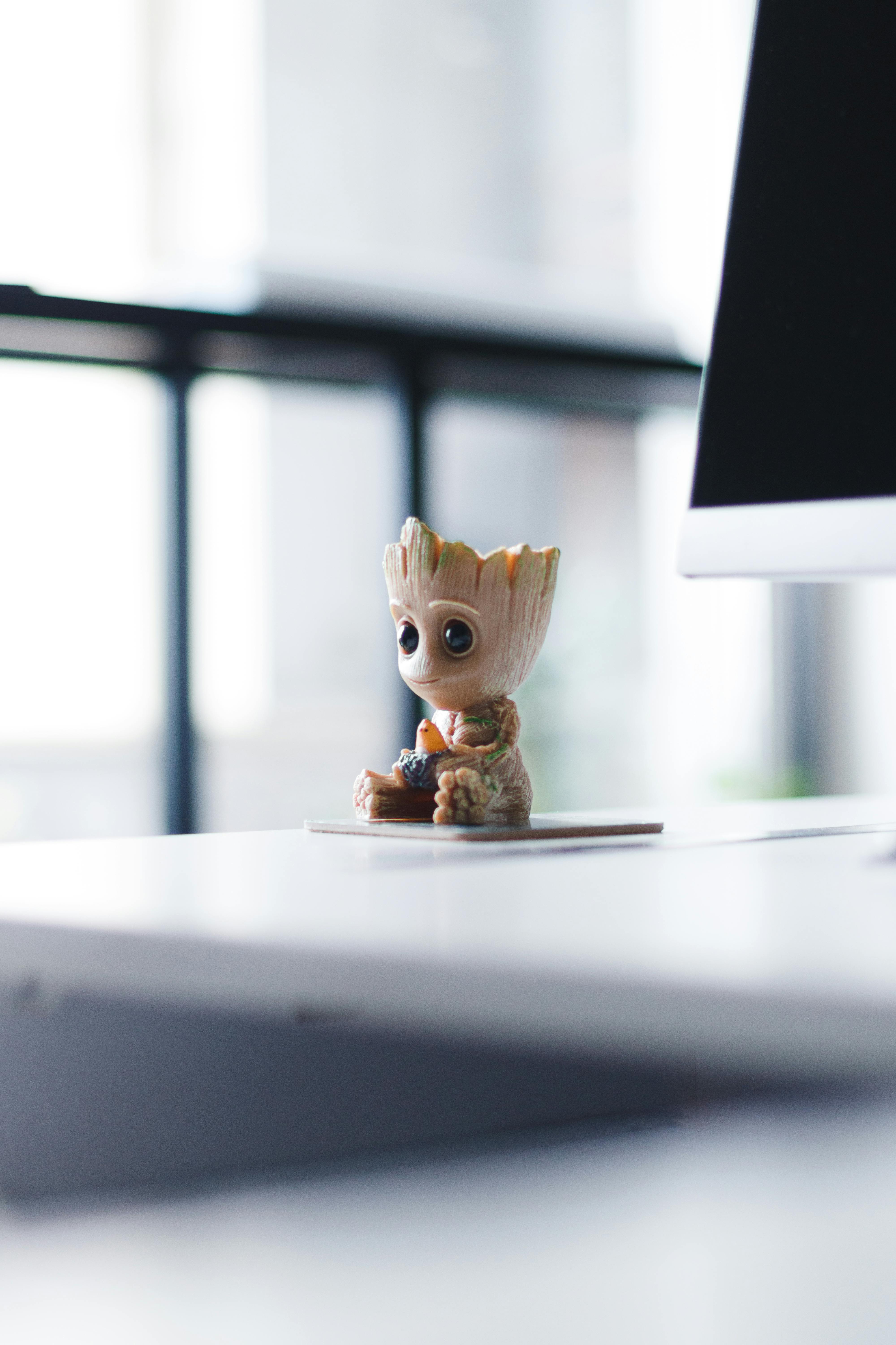 A small figurine of a baby groot sitting on a desk · Free Stock Photo