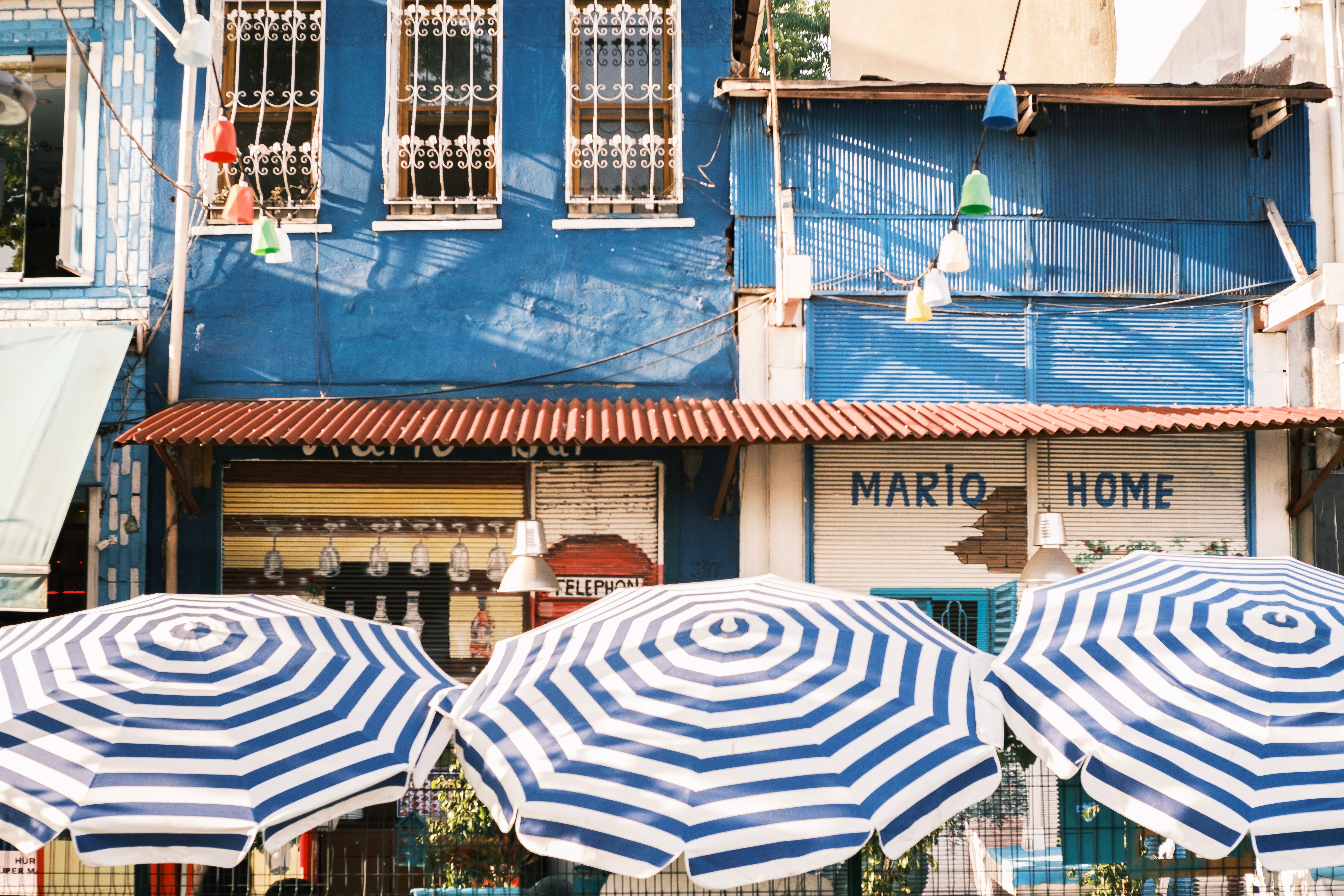 Blue and white striped umbrellas are in front of a blue building · Free ...