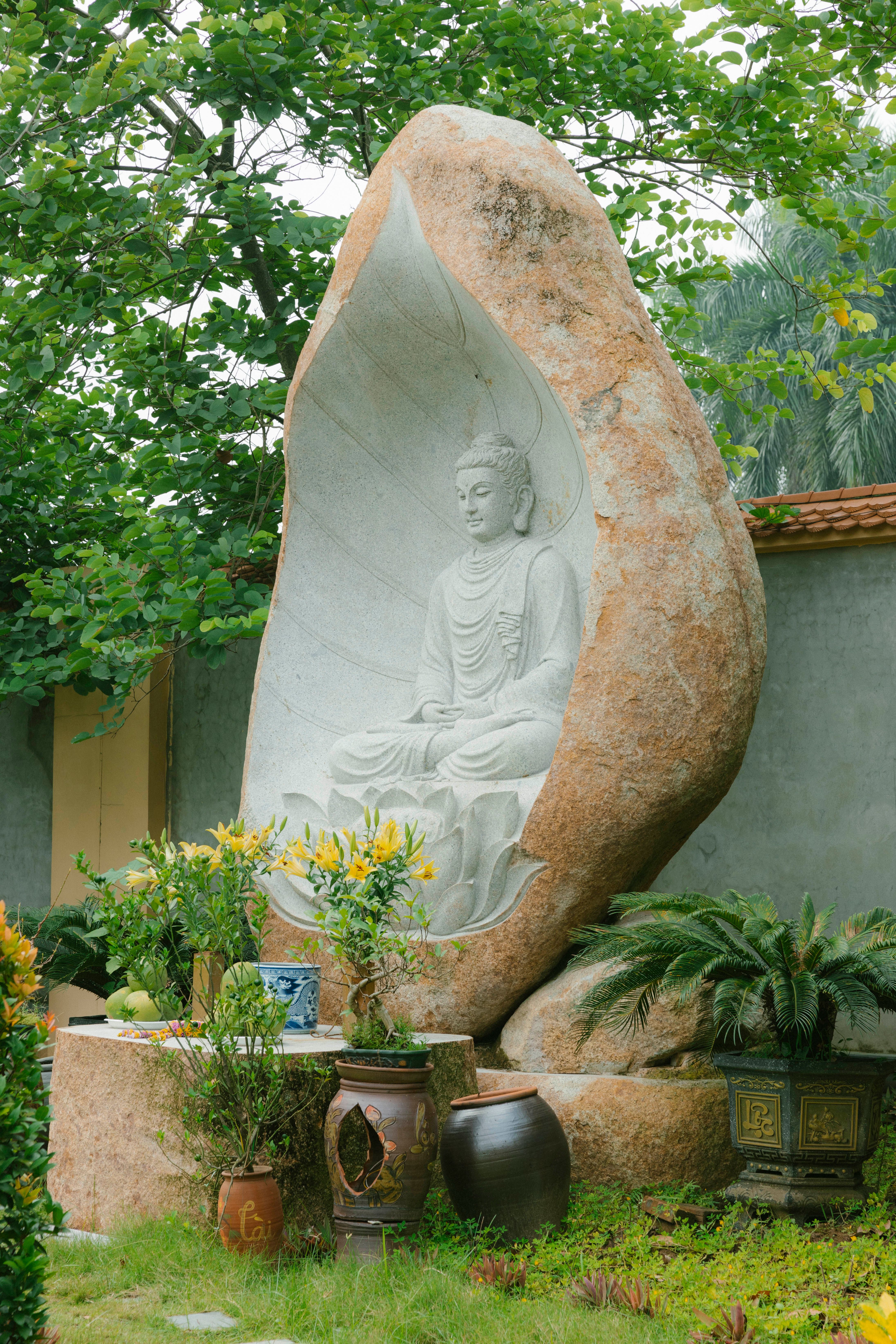 A large stone statue of buddha in a garden · Free Stock Photo