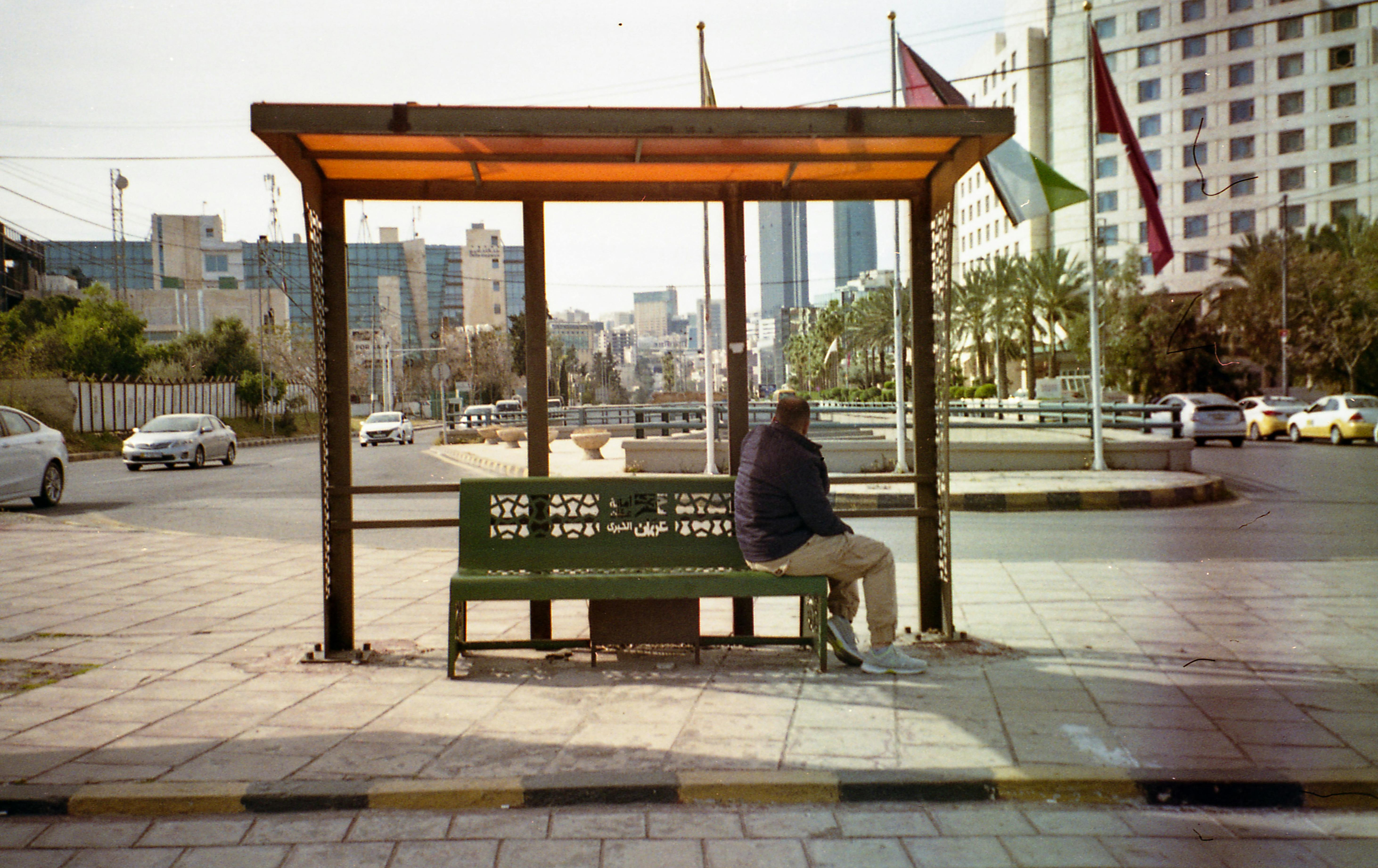 A man sitting on a bench at a bus stop · Free Stock Photo