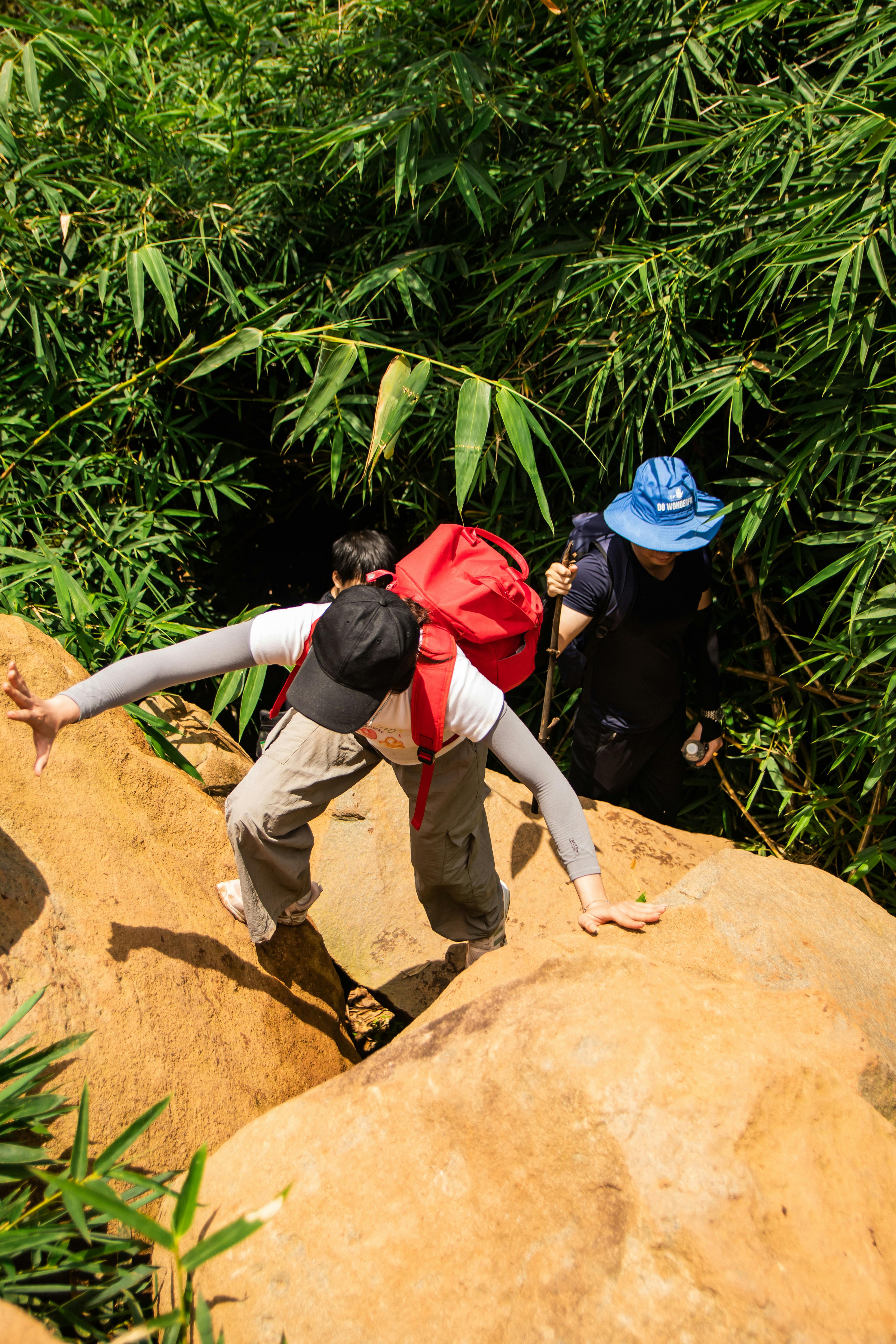 A man with a backpack is climbing up a rock · Free Stock Photo
