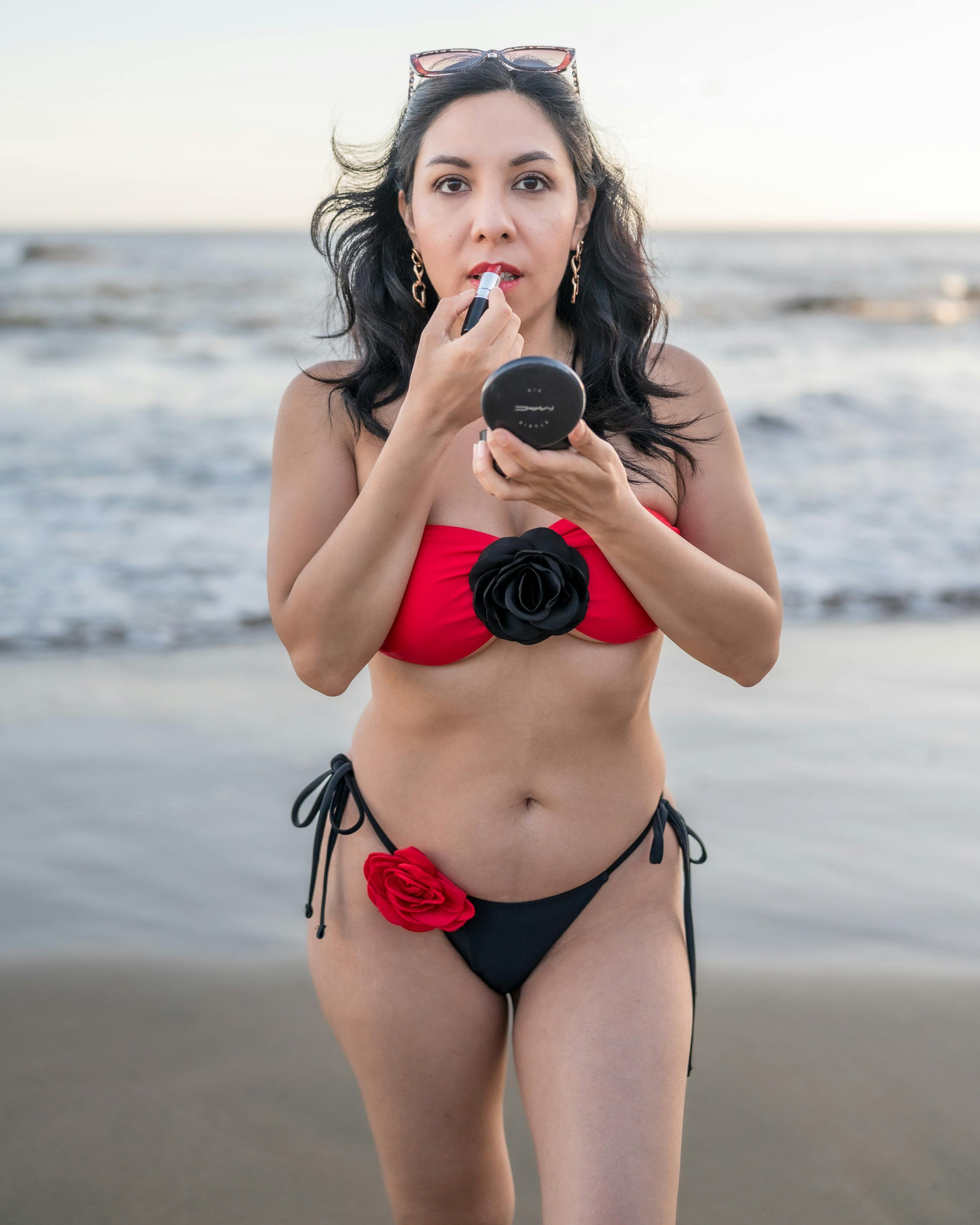 A woman in a red bikini and black panties is holding a lipstick · Free Stock Photo