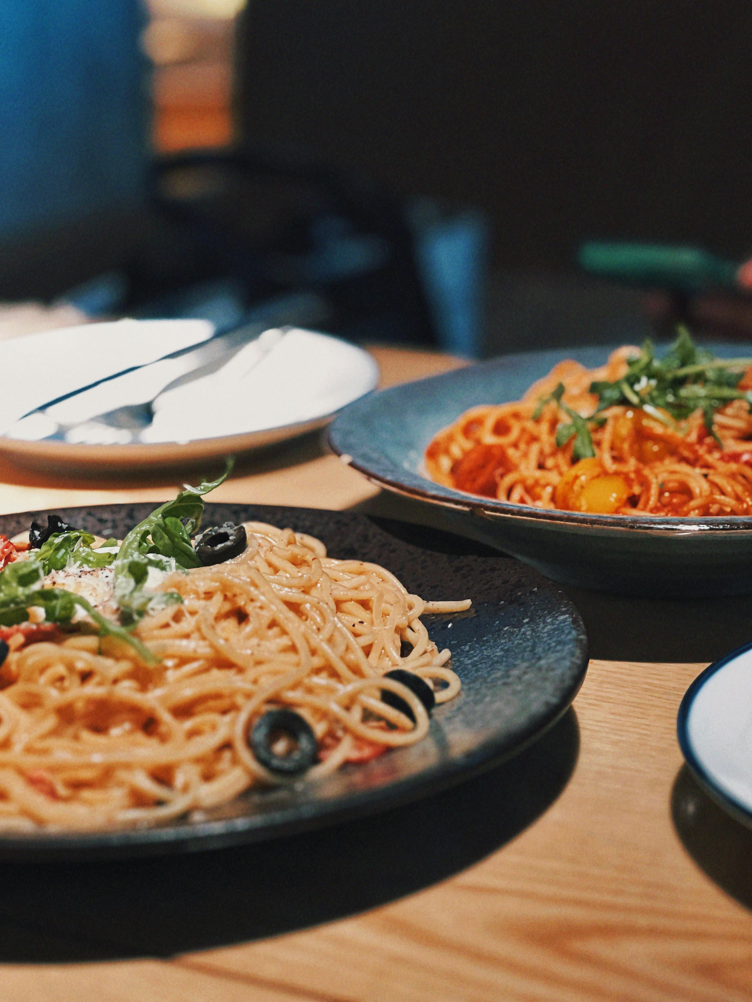 Two plates of spaghetti on a wooden table · Free Stock Photo
