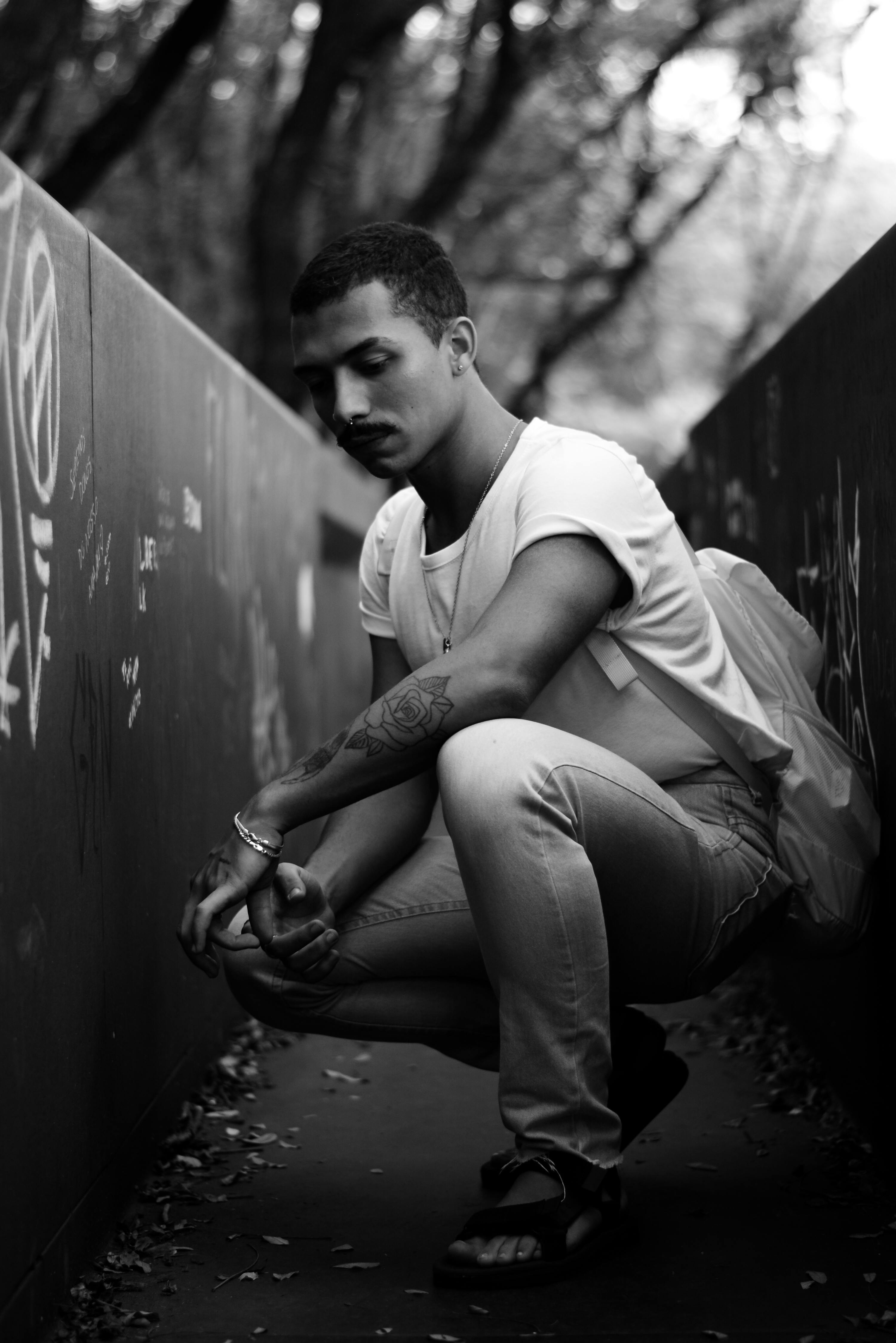 A man crouching down on a concrete wall with graffiti · Free Stock Photo