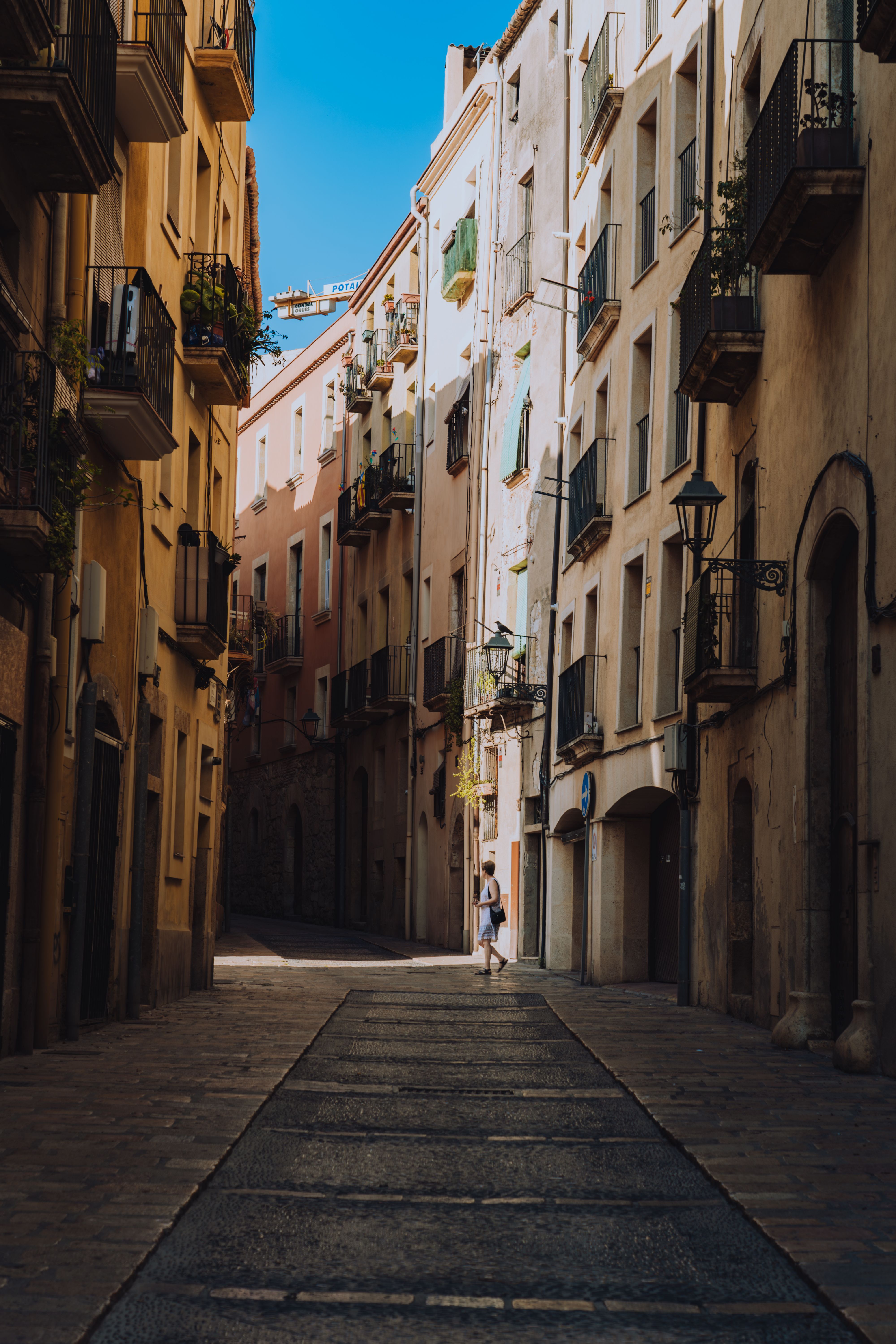 A person walking down a narrow street in a city · Free Stock Photo