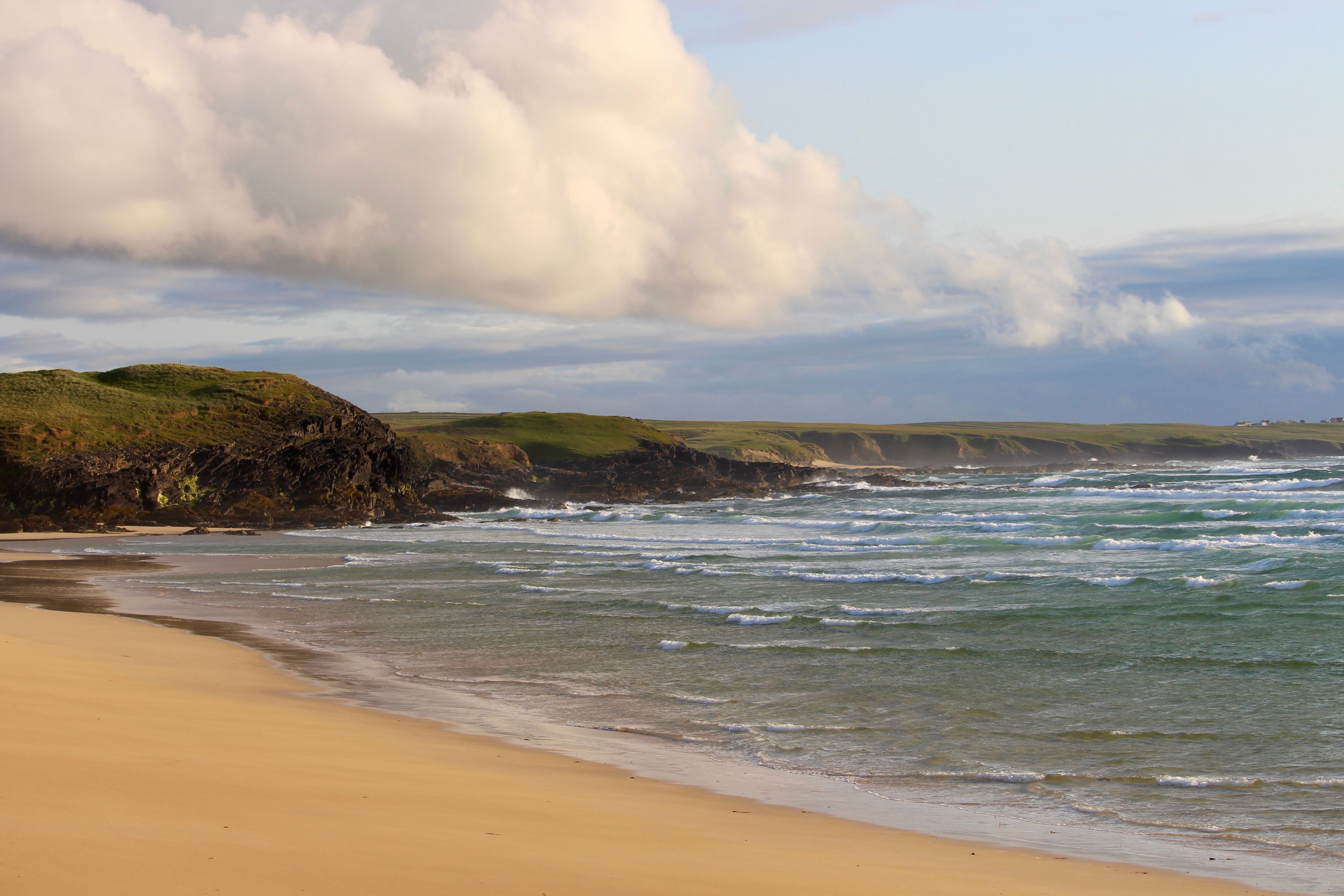 A sandy beach with a body of water in the background · Free Stock Photo