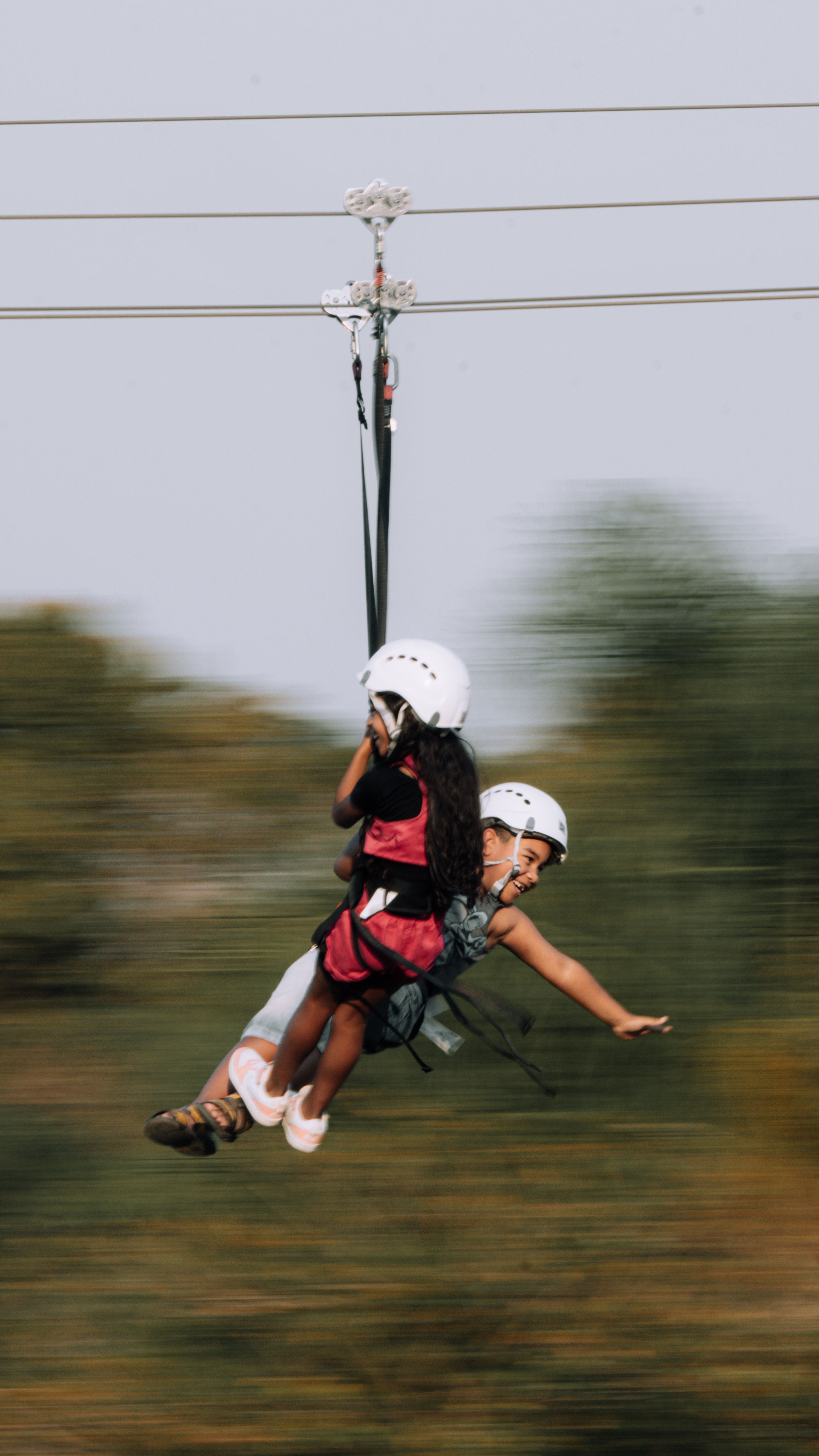 Two people riding on a zip line in the air · Free Stock Photo